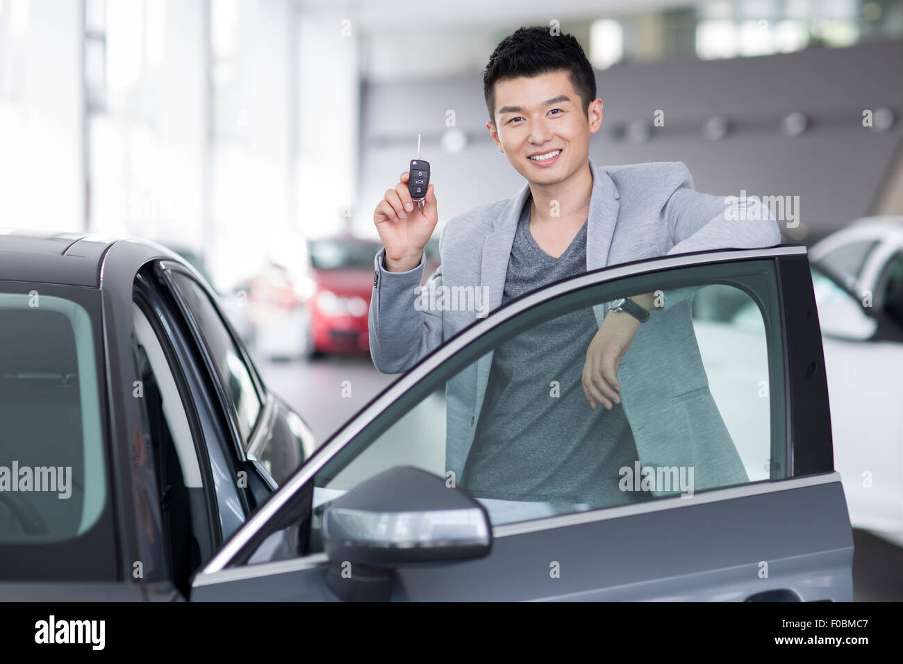 Young man buying car in showroom Stock Photo - Alamy