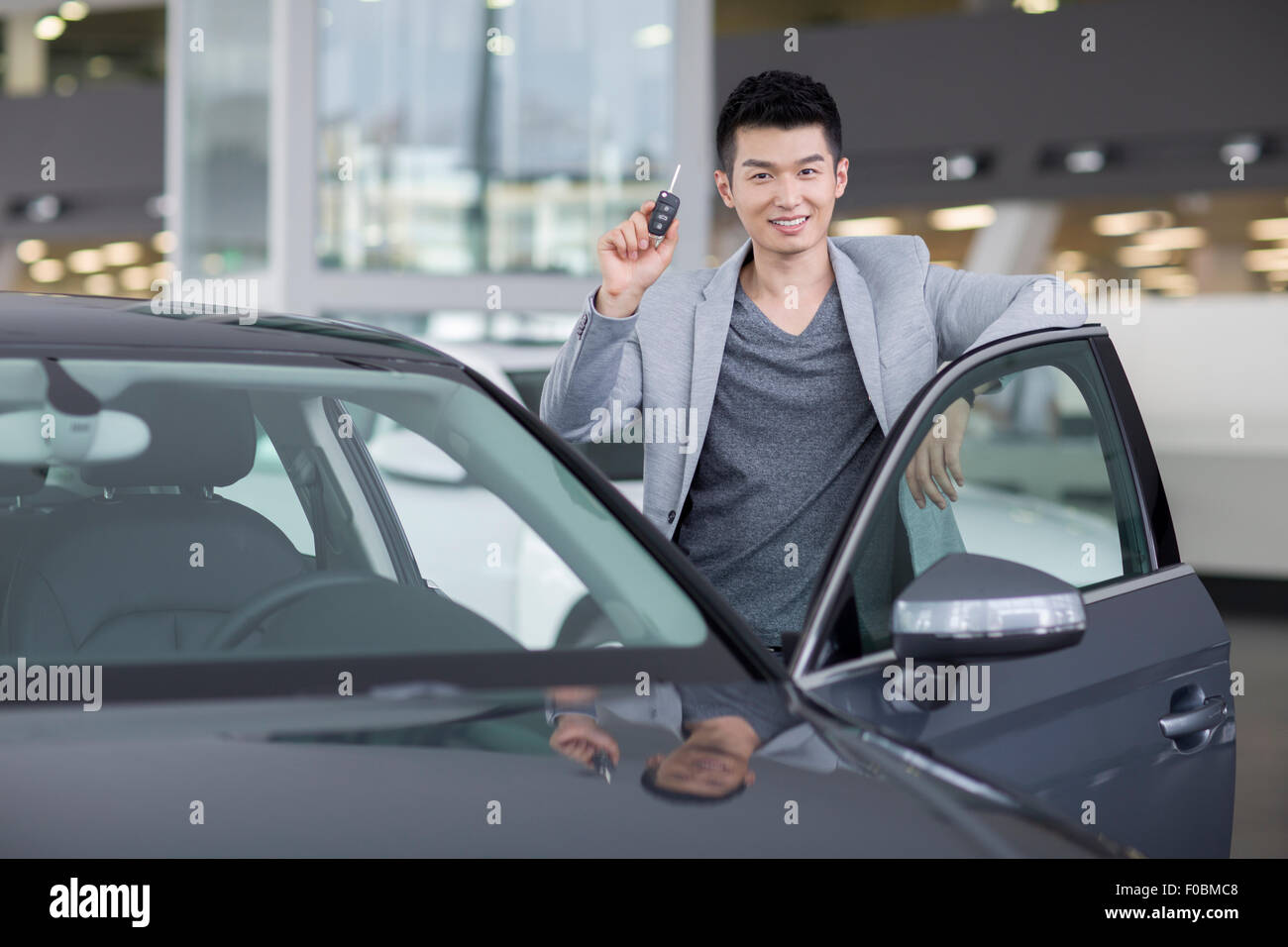 Young man buying car in showroom Stock Photo - Alamy