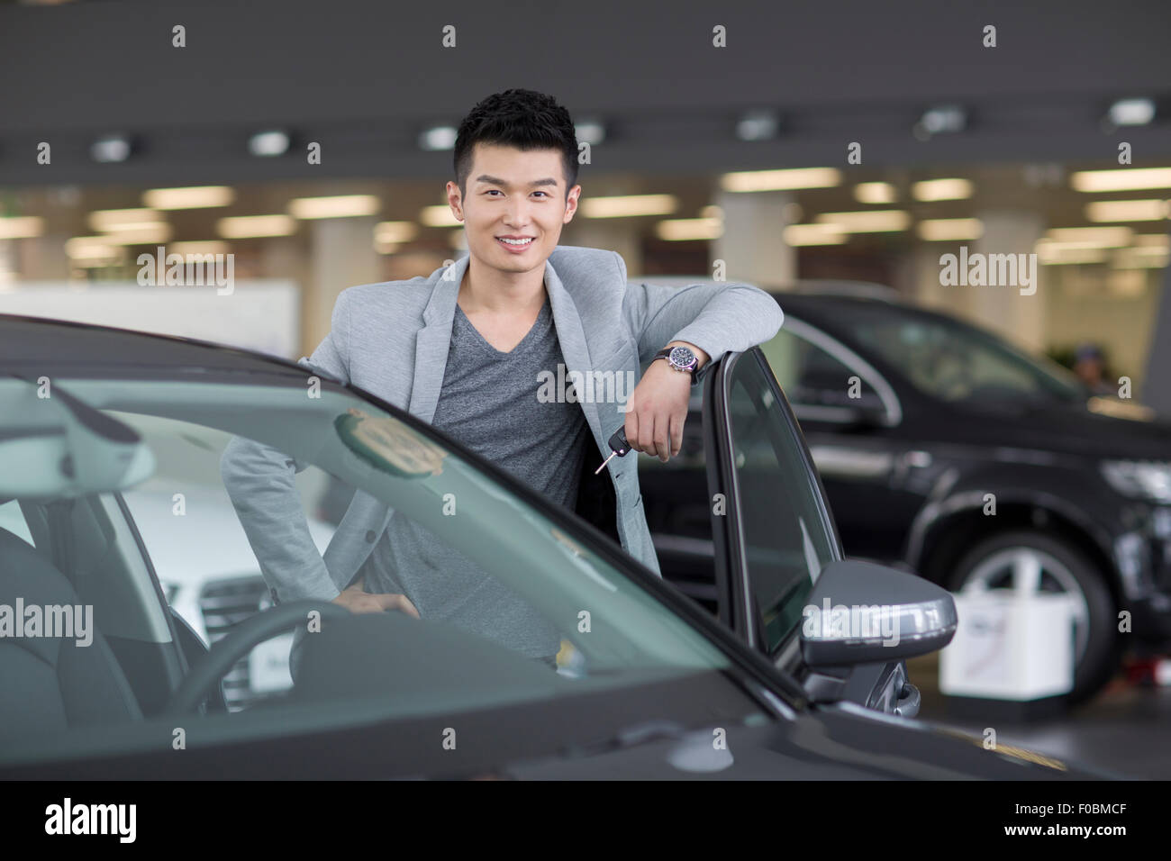 Young man buying car in showroom Stock Photo - Alamy