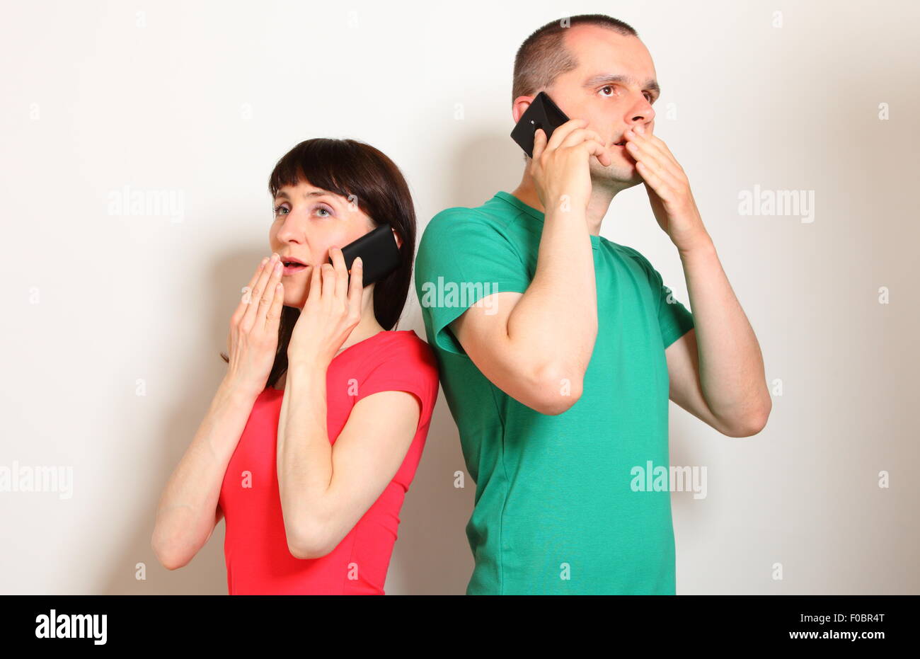 Shocked woman and man receive an unexpected message while talking on ...