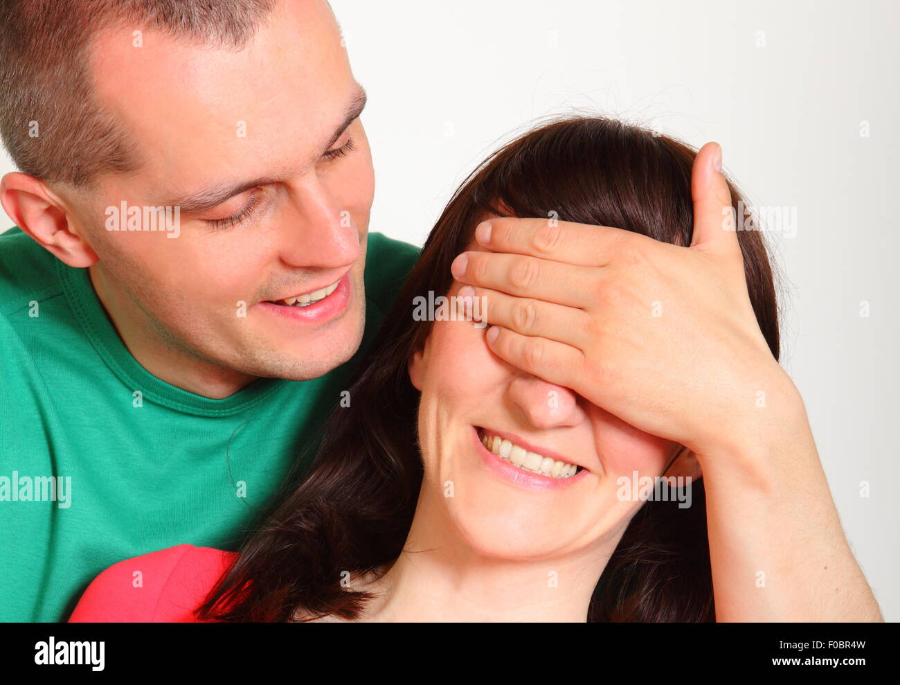 Husband covering eyes of his wife for surprise, young couple having fun ...