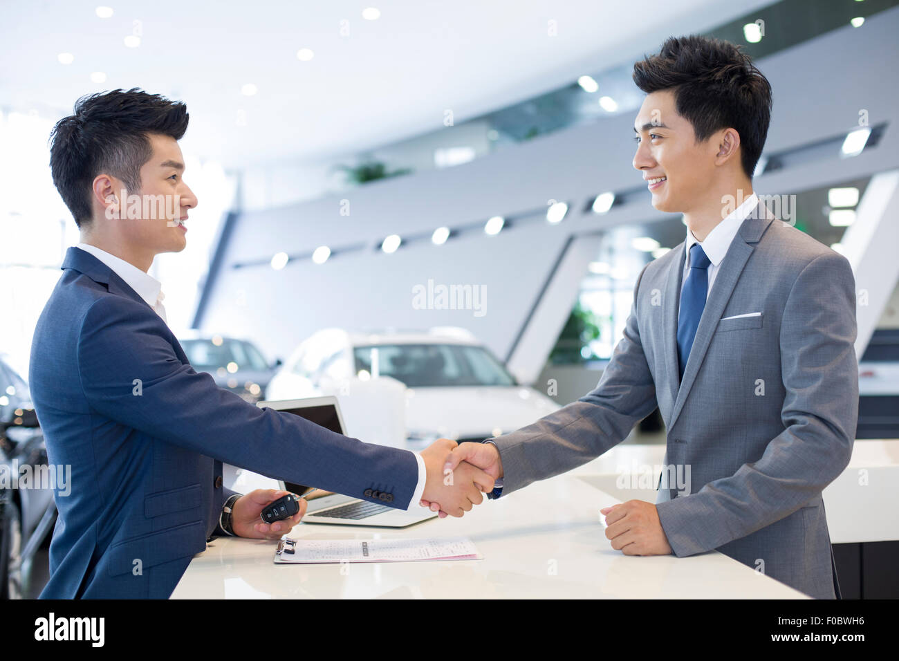 Young man buying car in showroom Stock Photo - Alamy
