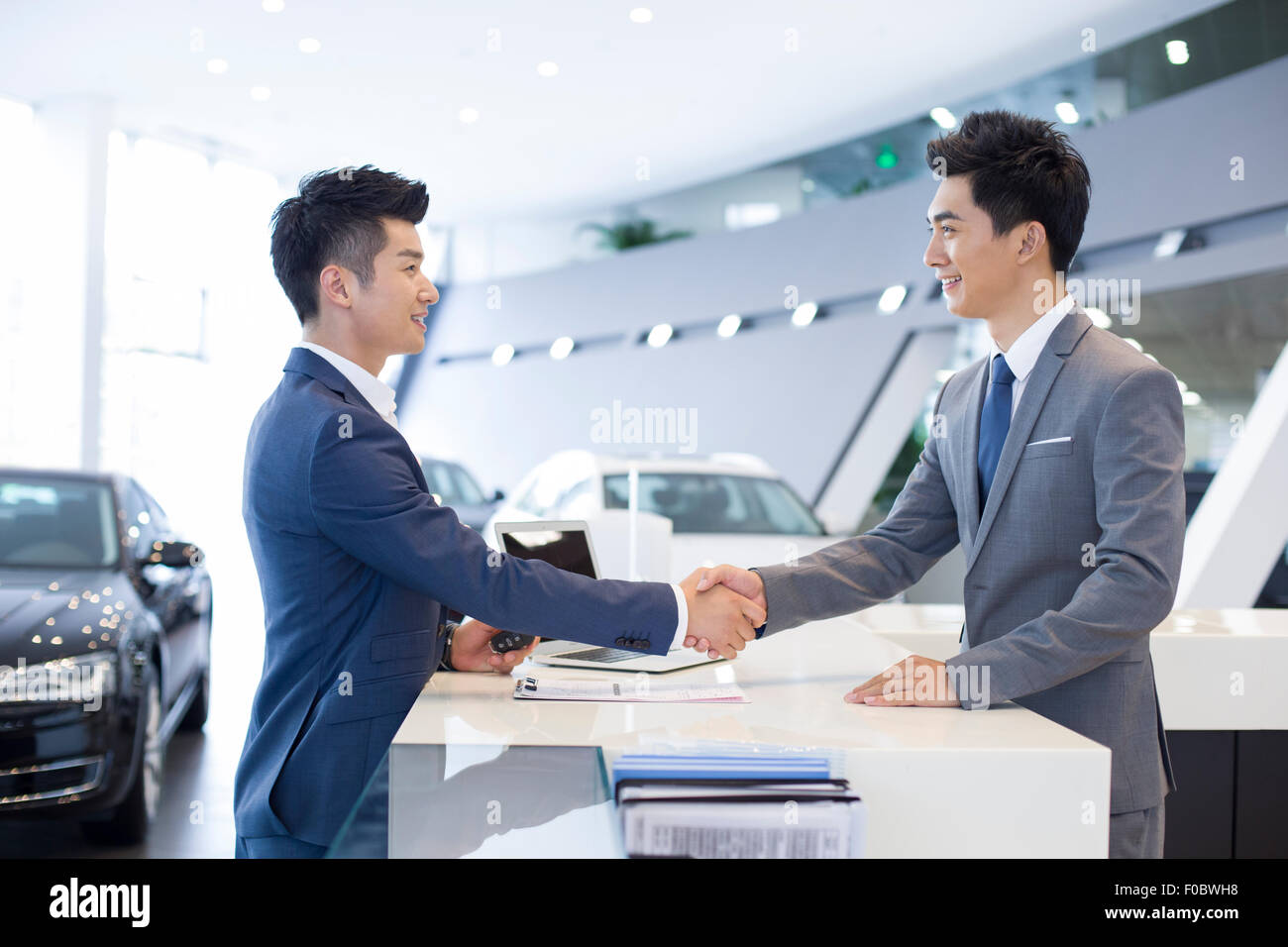 Young man buying car in showroom Stock Photo - Alamy