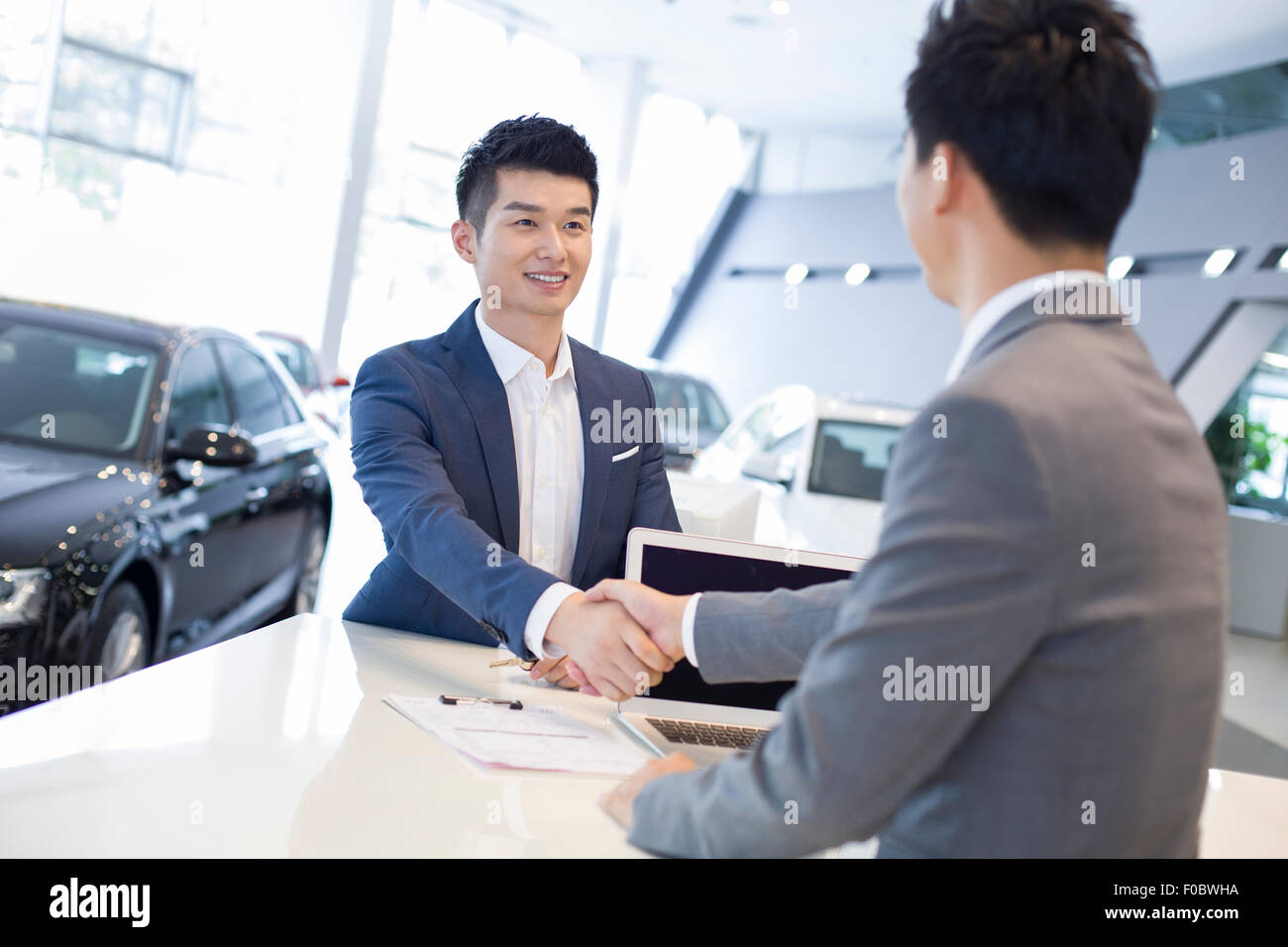 Young man buying car in showroom Stock Photo - Alamy