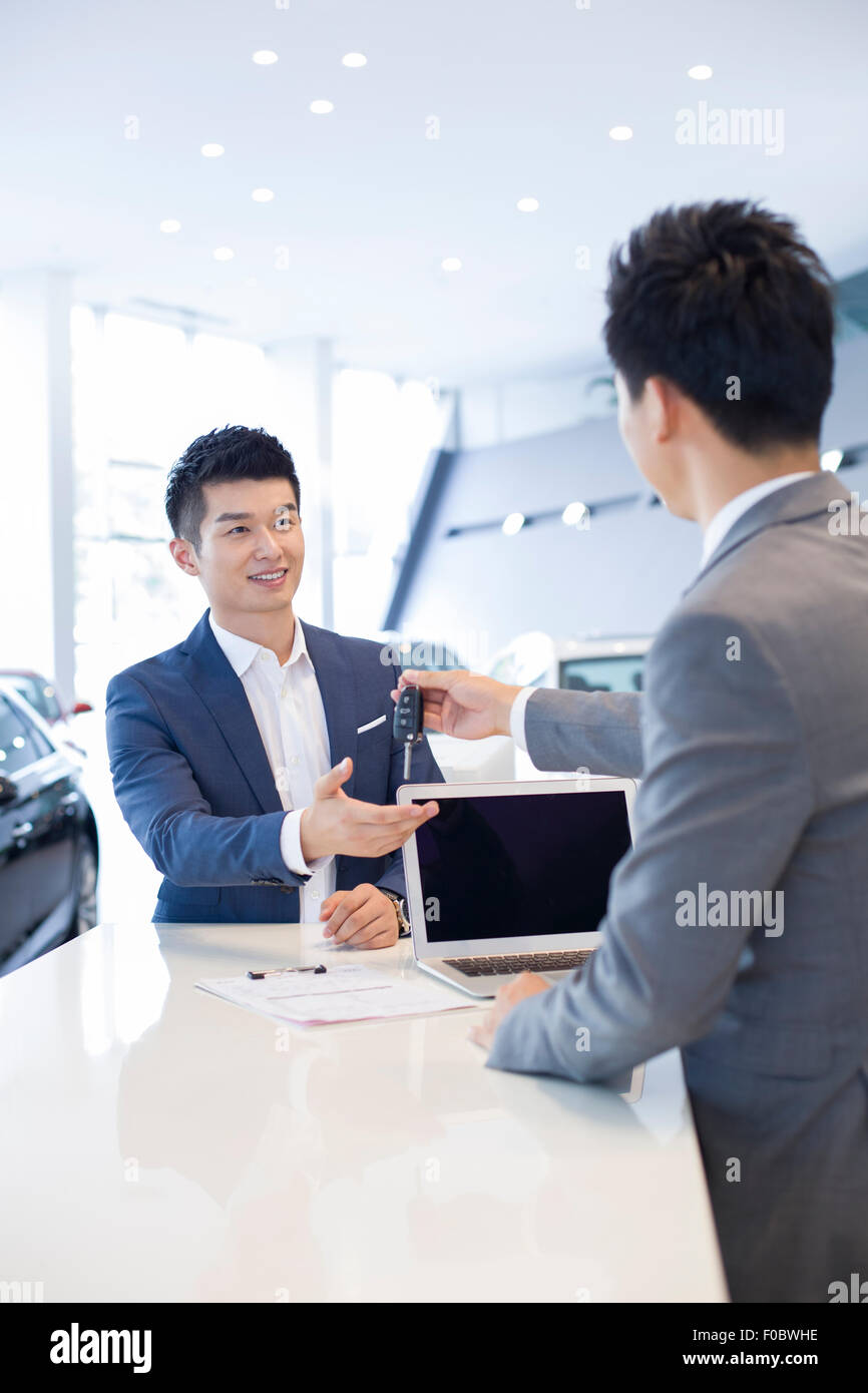 Young man buying car in showroom Stock Photo - Alamy