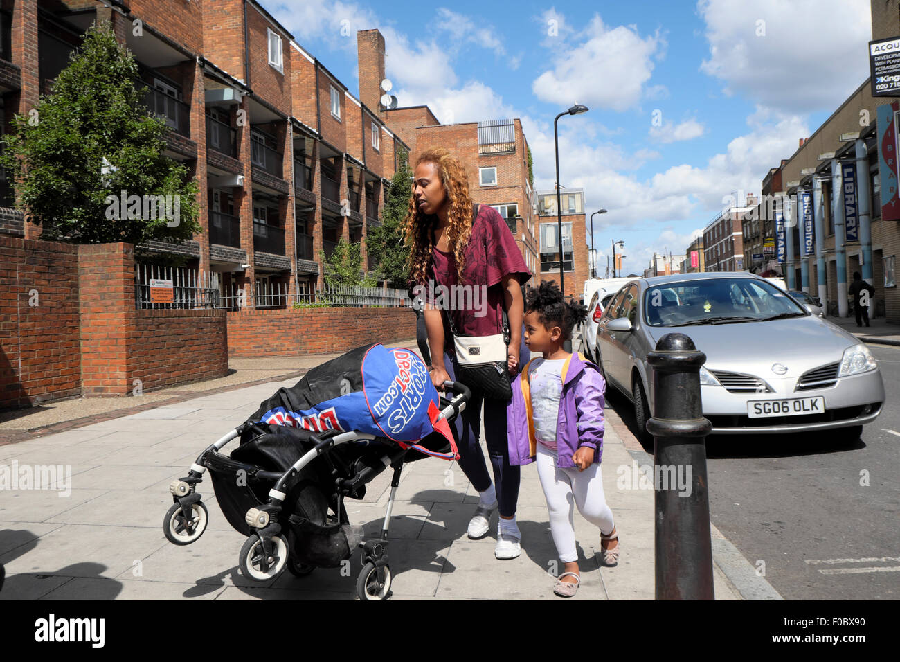A mother pushes a bag of launder in a pushchair holding child's hand on ...