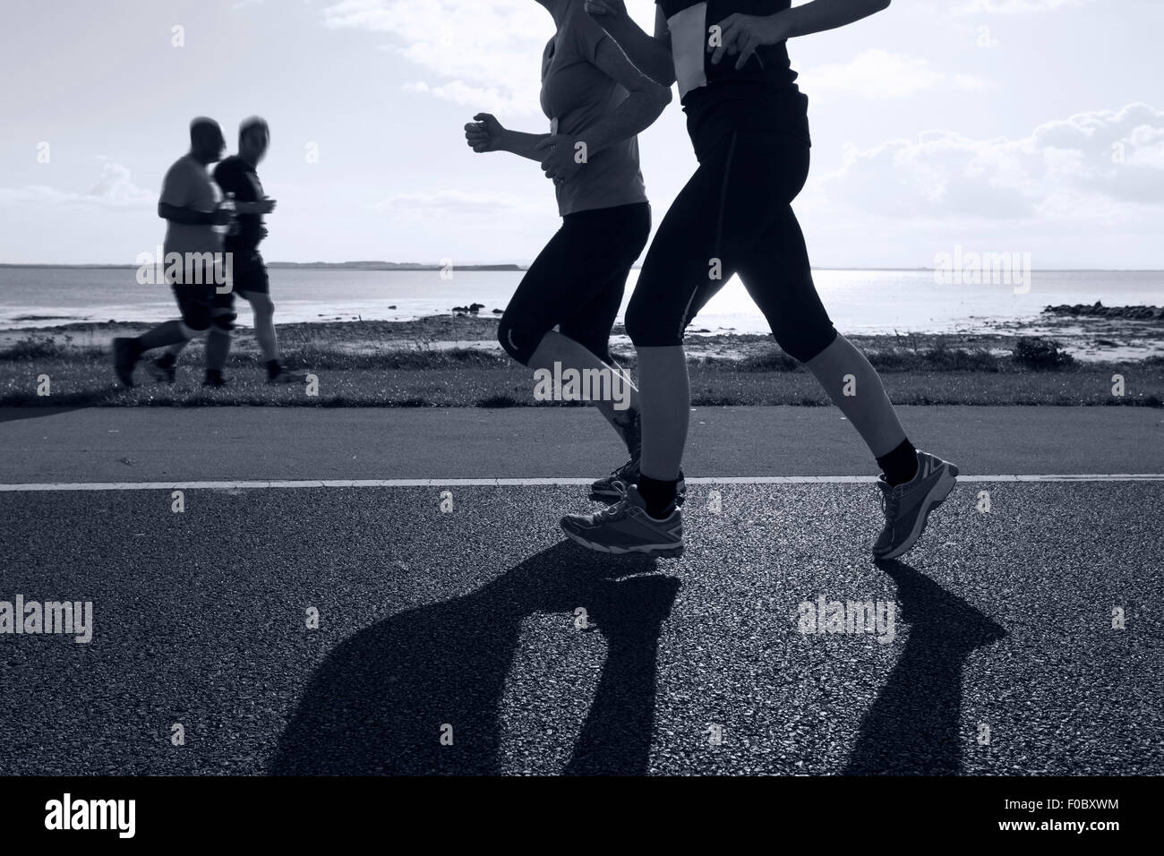 Group of runners compete in the race on coastal road Stock Photo - Alamy