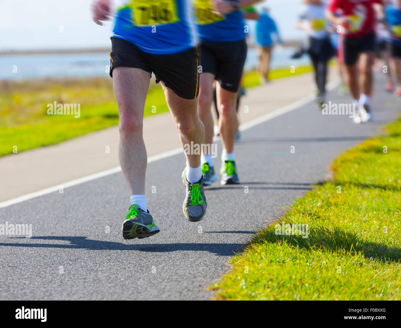Group of runners compete in the race on coastal road Stock Photo - Alamy