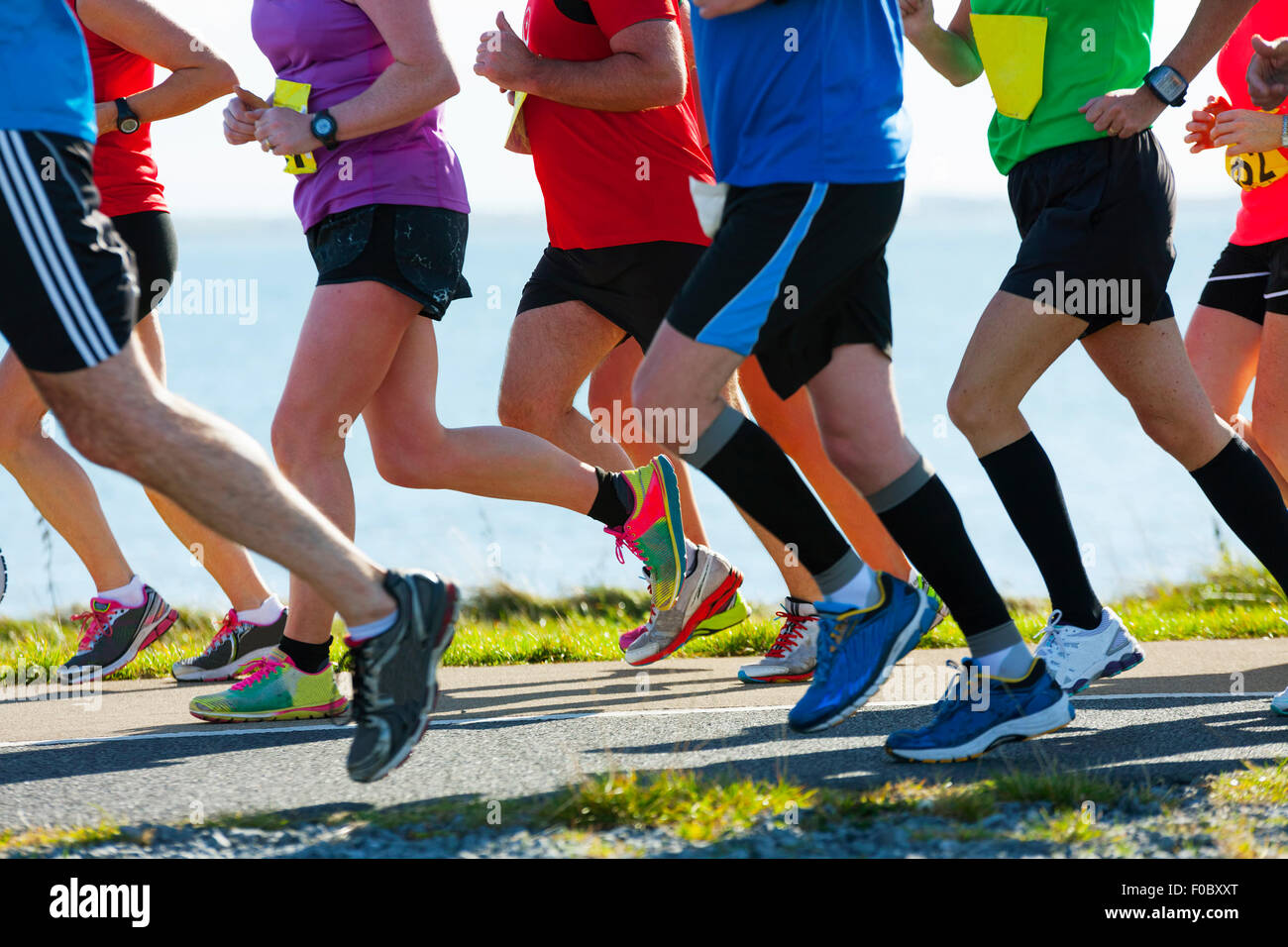 Group of runners compete in the race on coastal road Stock Photo - Alamy