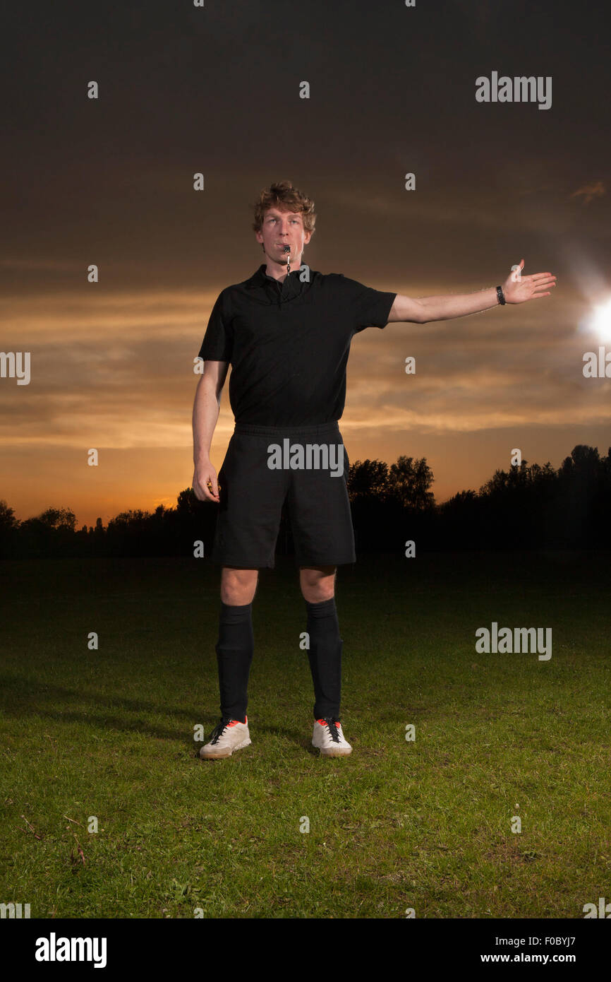 Referee signaling while blowing whistle on soccer field Stock Photo - Alamy