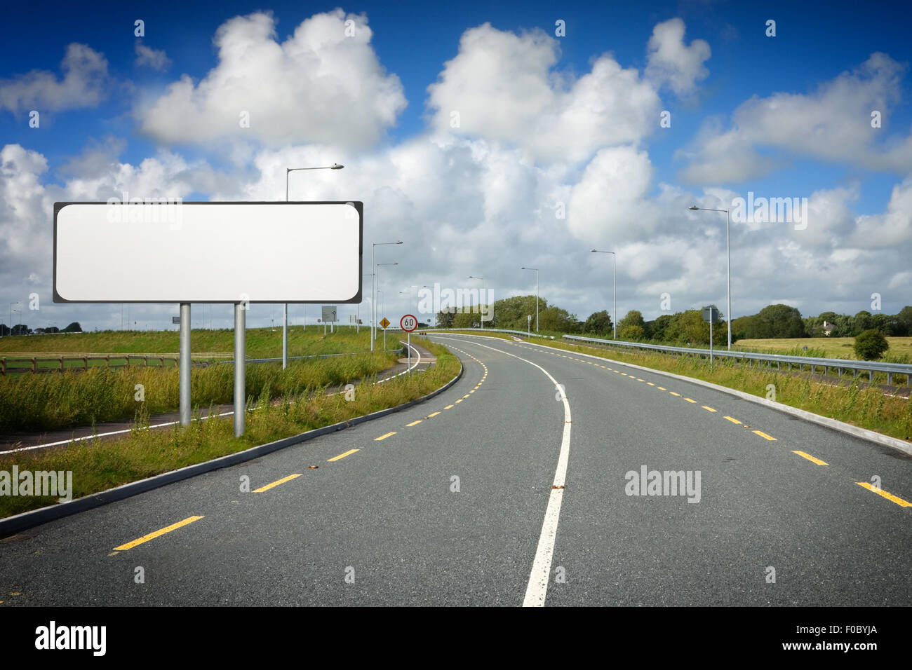new motorway with road markings and white sign at sunny day with clouds ...