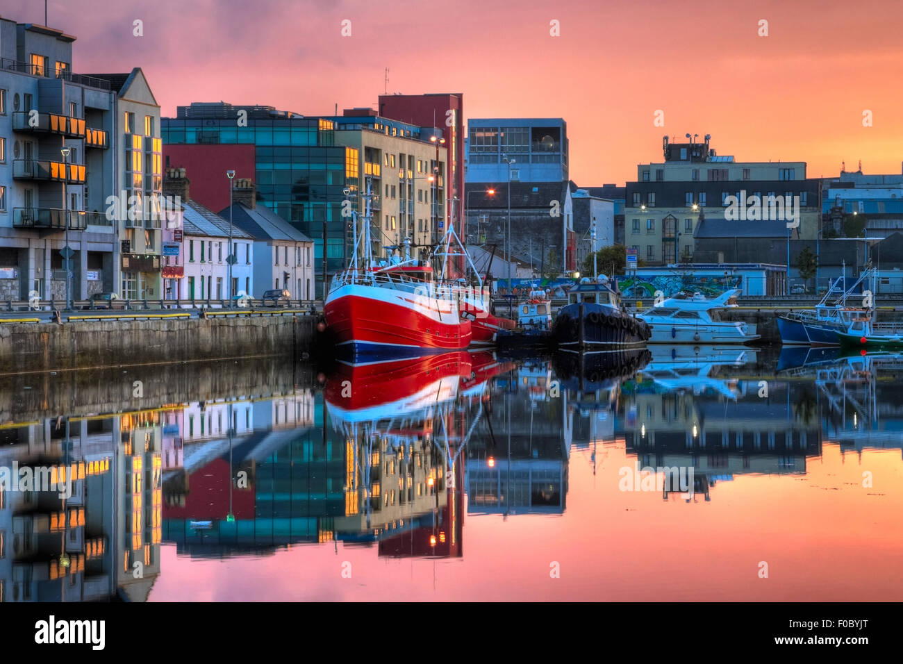 morning view on row of buildings and fishing boats in Galway Dock with ...
