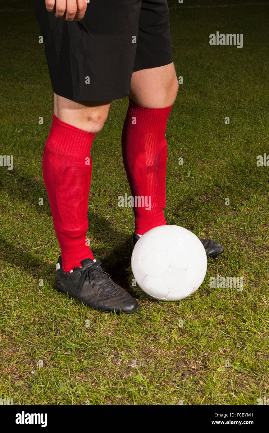 Low section of young soccer player with ball on field Stock Photo - Alamy