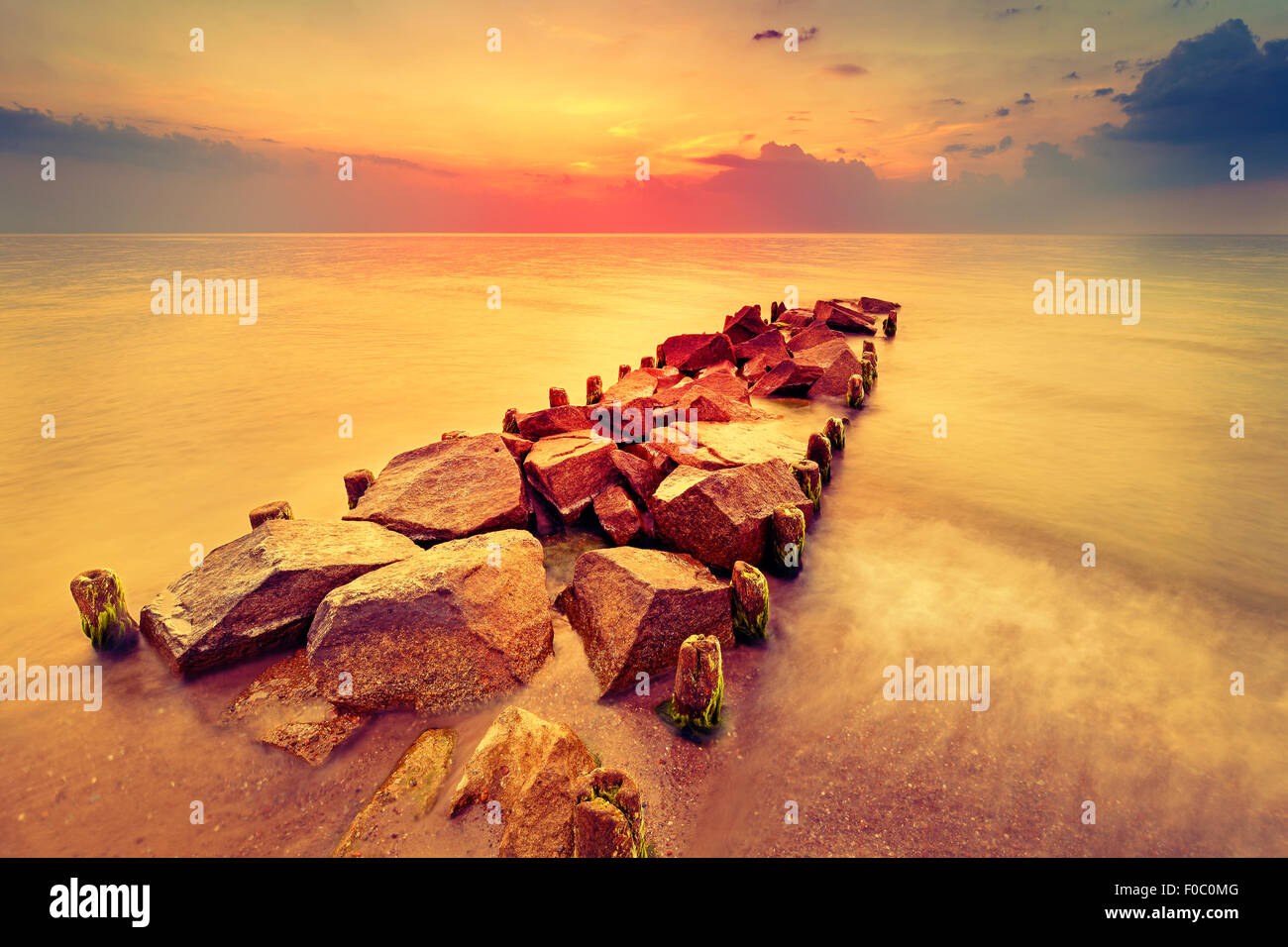 Beautiful sunset over beach and rocky pier Stock Photo - Alamy