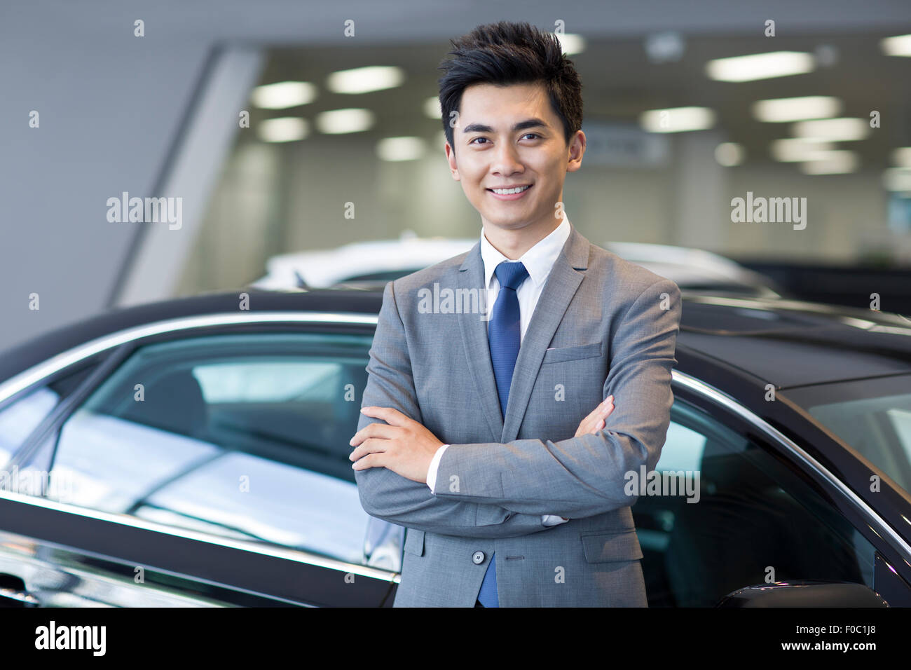 Confident car salesperson standing with arms crossed Stock Photo - Alamy