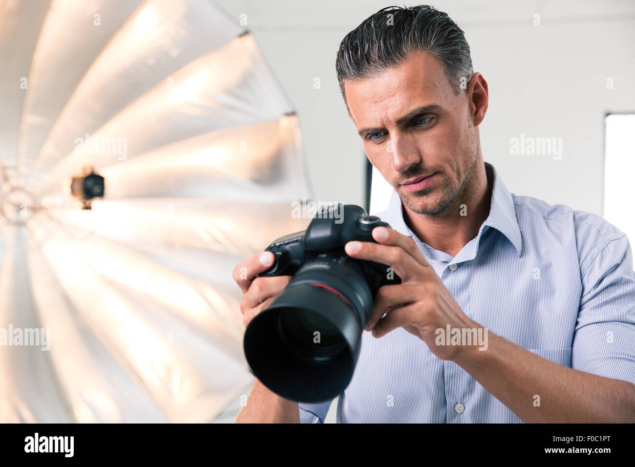 Portrait of a confident photographer using camera in studio Stock Photo ...