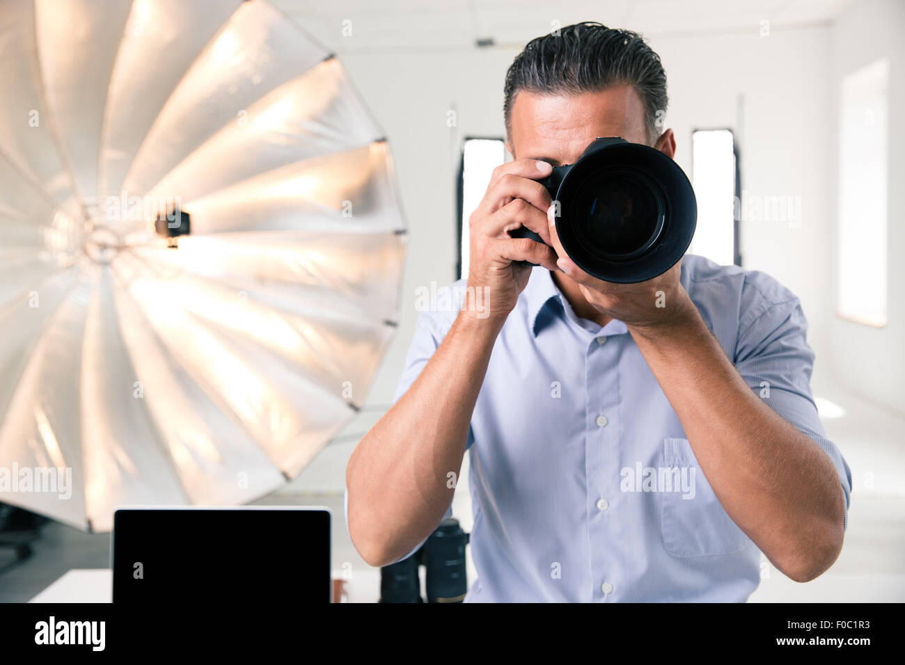 Photographer making photo on camera in studio Stock Photo - Alamy