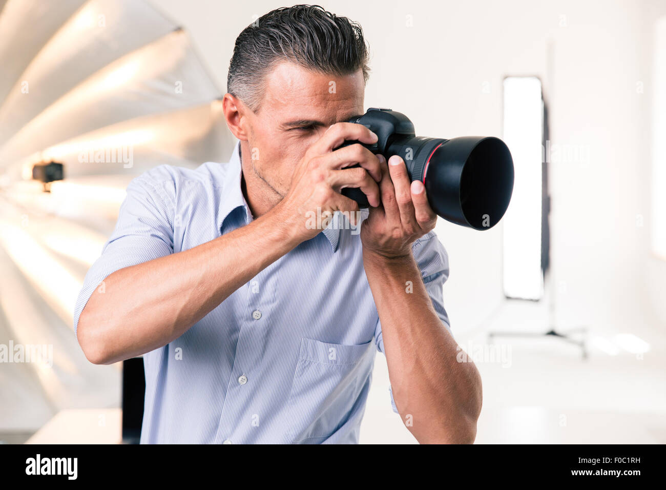 Handsome photographer making photo on camera in studio Stock Photo - Alamy