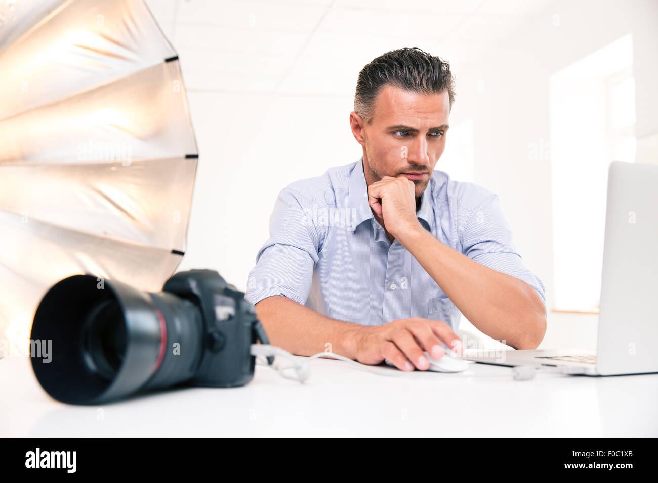 Portrait of a handsome photographer using laptop at his workplace Stock ...