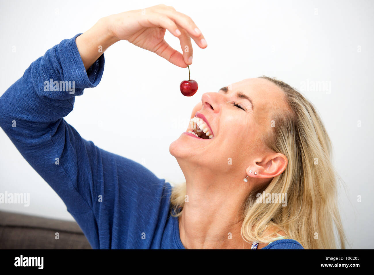 portrait of blond woman eating a cherry Stock Photo - Alamy