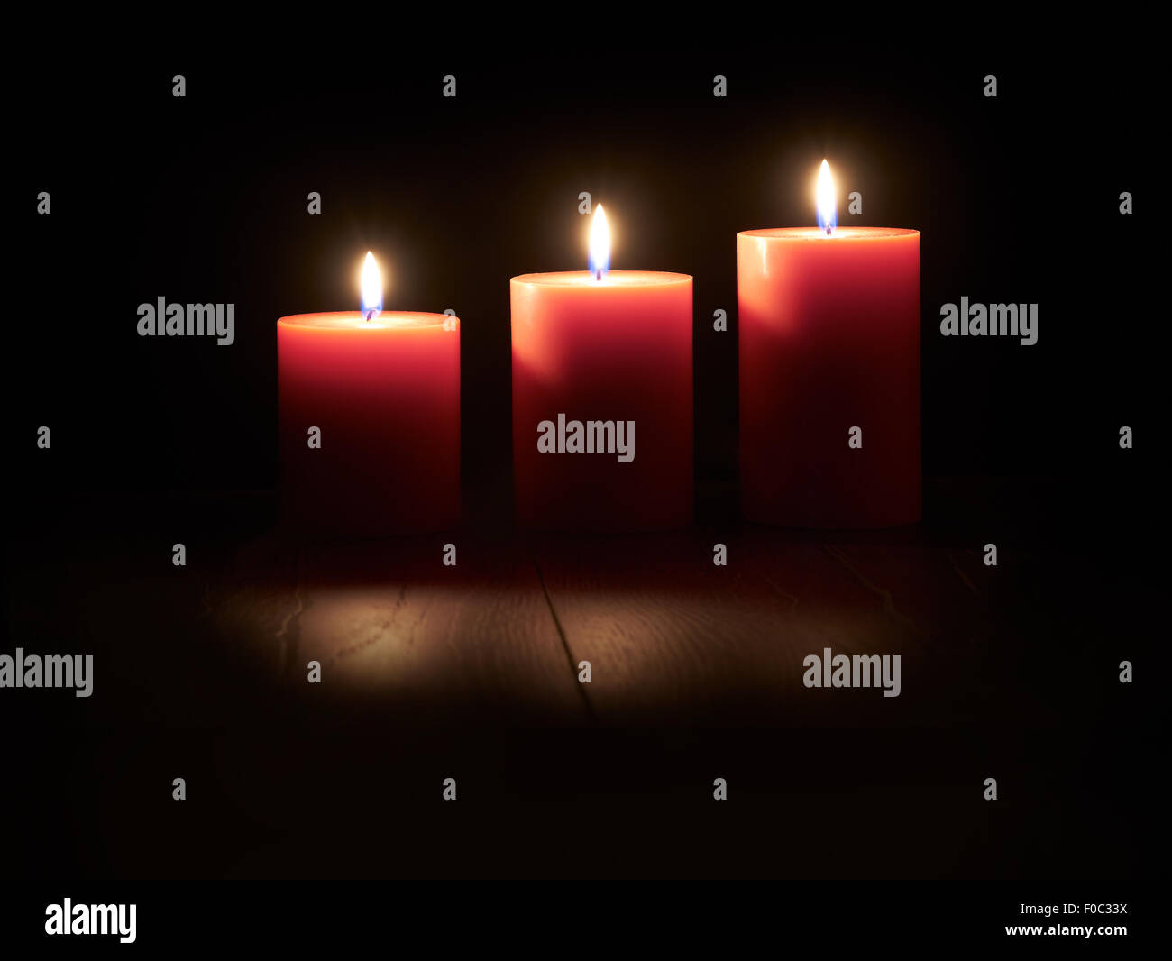 Lit red candles on a dark wooden floor with black background Stock ...