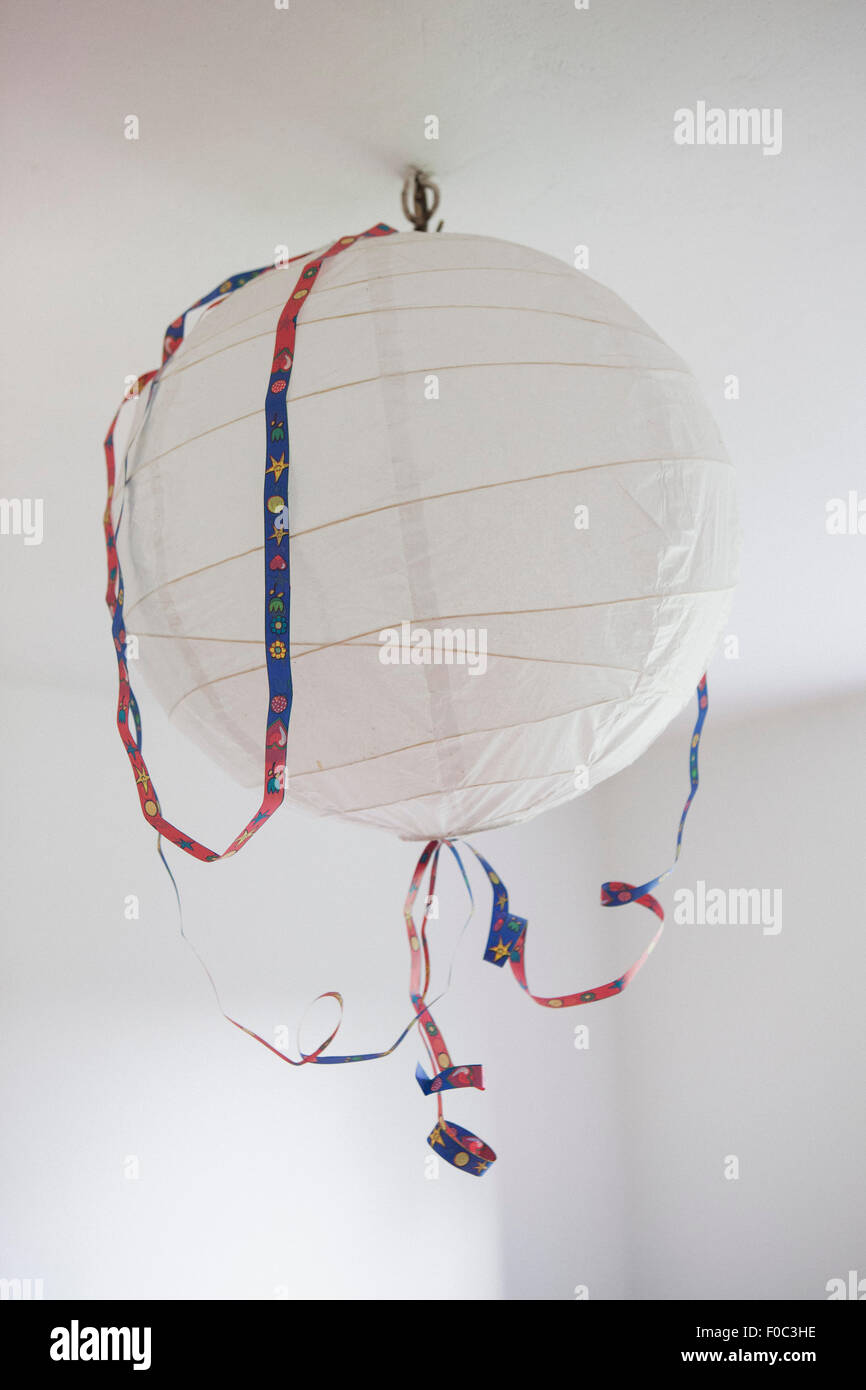 A paper lantern hanging from ceiling with a streamer around it Stock ...