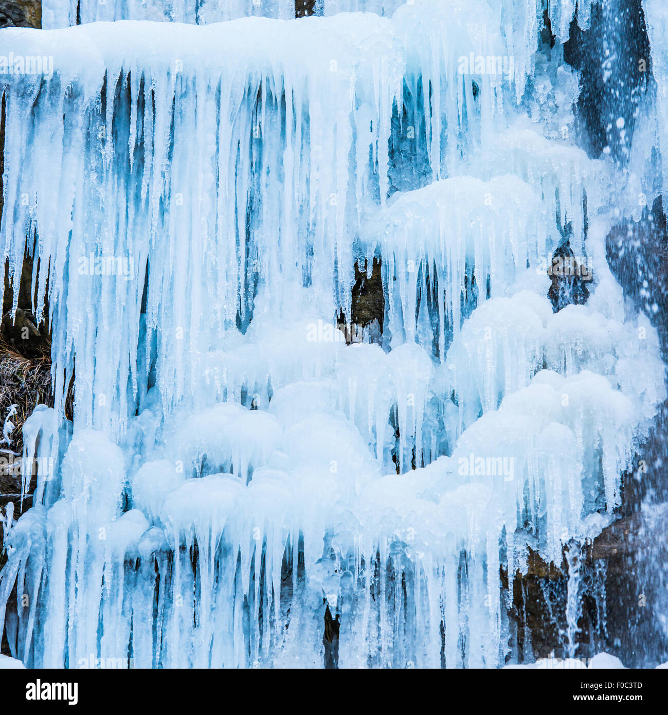 Frozen waterfall of blue icicles on the rock Stock Photo - Alamy