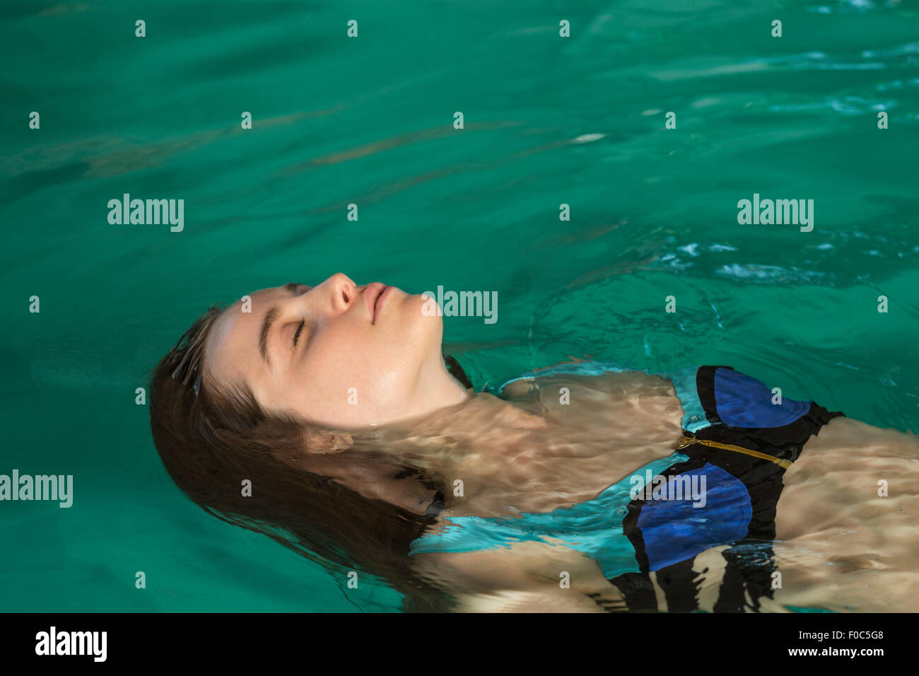 Beautiful young woman floating in swimming pool Stock Photo - Alamy