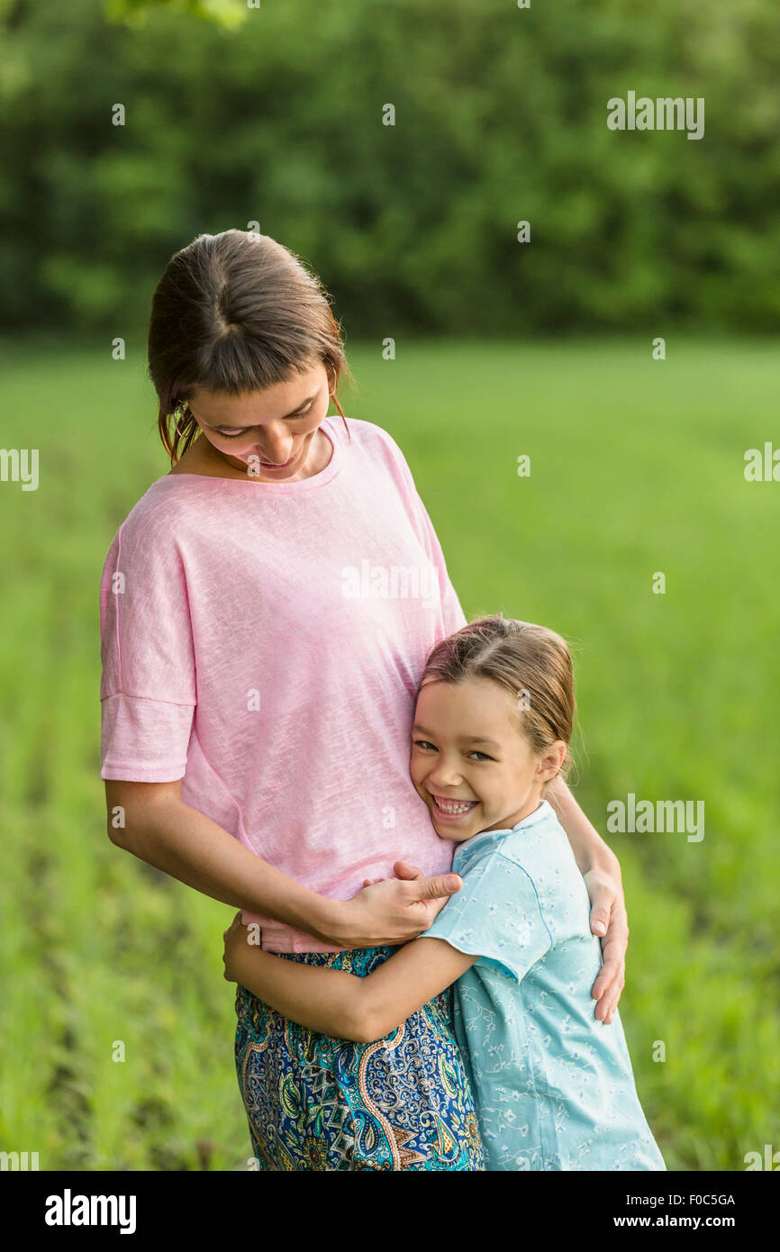 Smiling girl hugging mother on field Stock Photo - Alamy