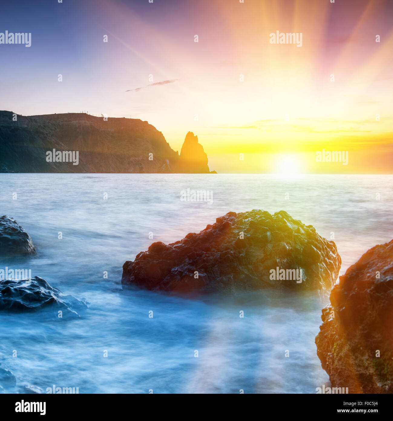 Sunset on the beach with sea, rocks and dramatic sky Stock Photo - Alamy