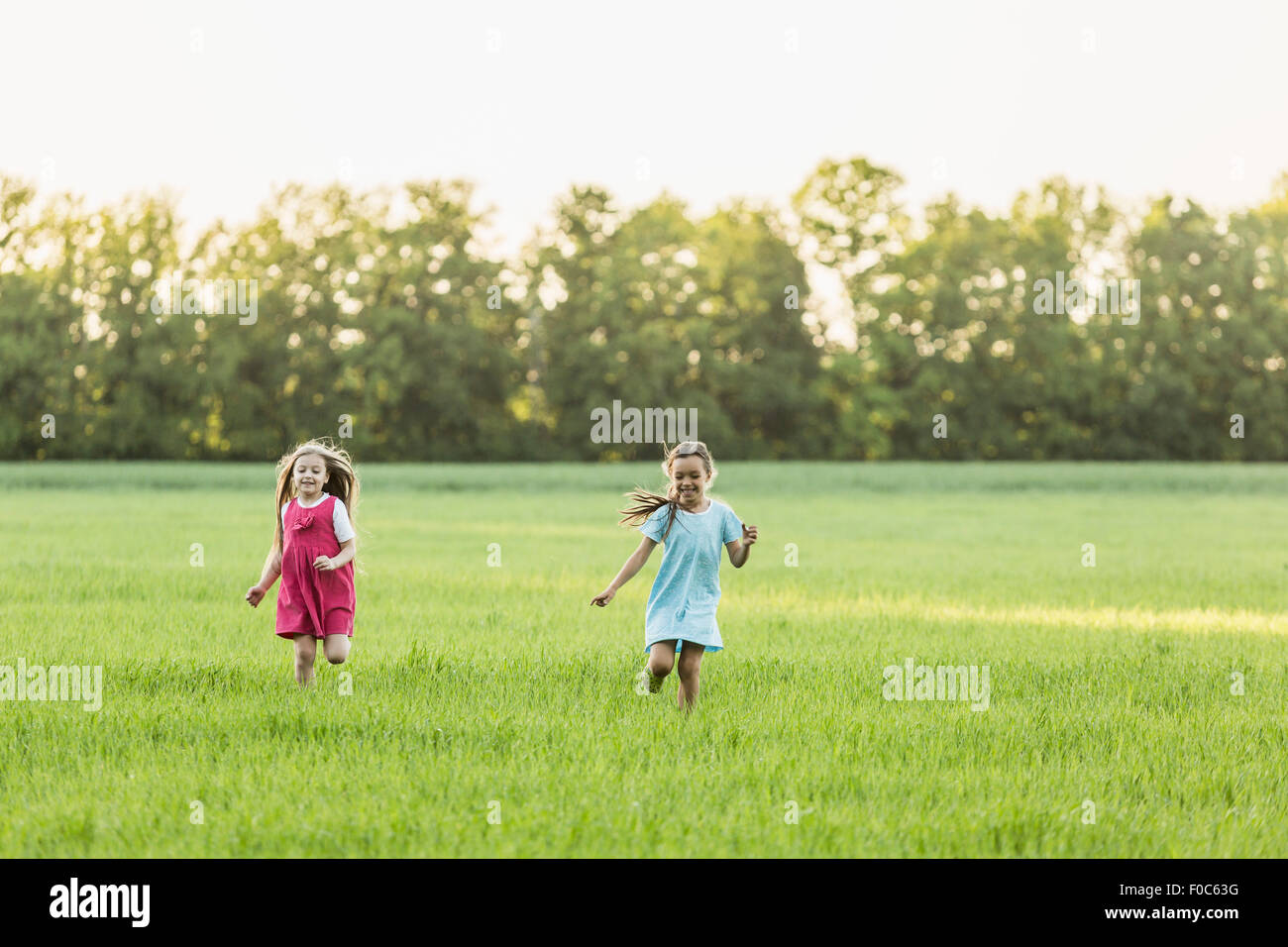 Girls running on grassy field Stock Photo - Alamy
