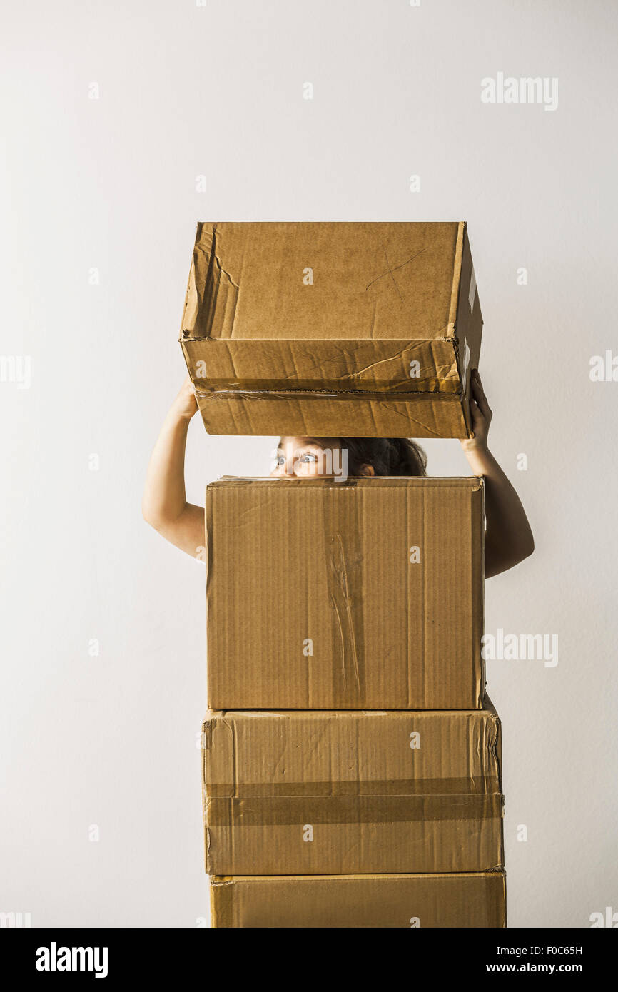 Girl looking away while stacking boxes against white background Stock ...