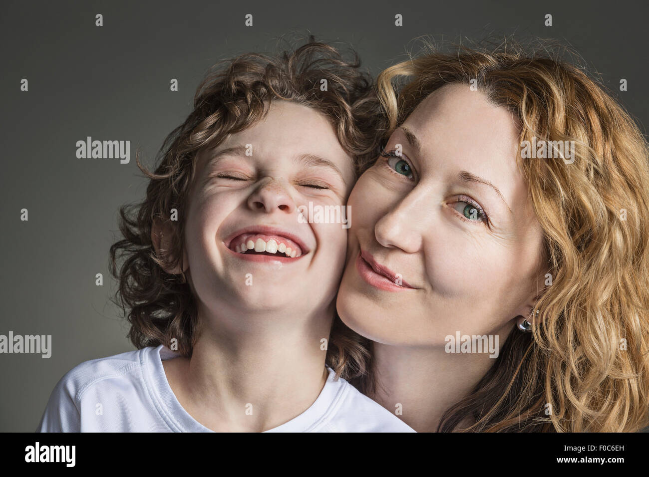 Close-up portrait of mother with cheerful son over gray background ...