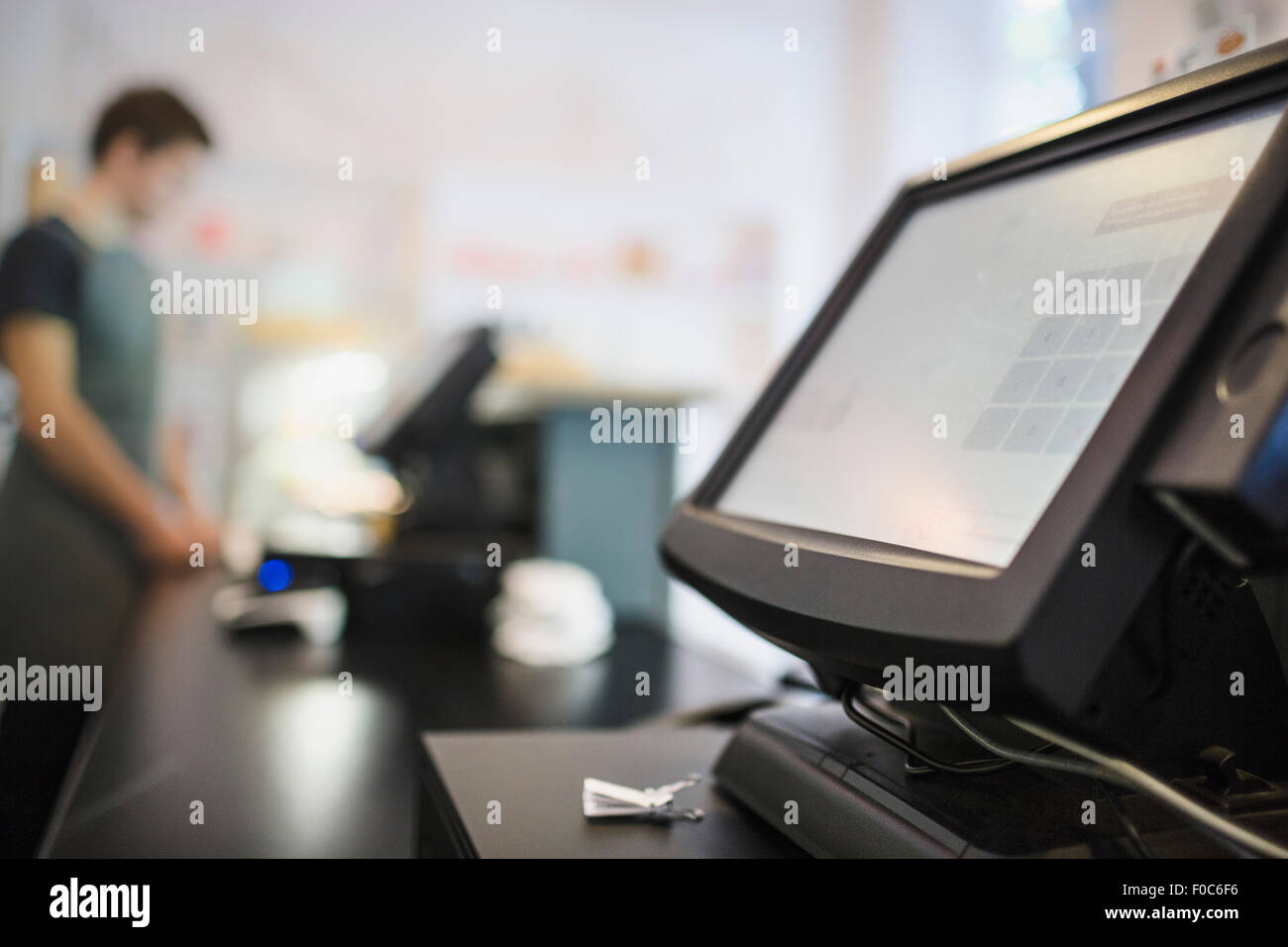 Close-up of checkout counter with cashier in background at coffee shop ...