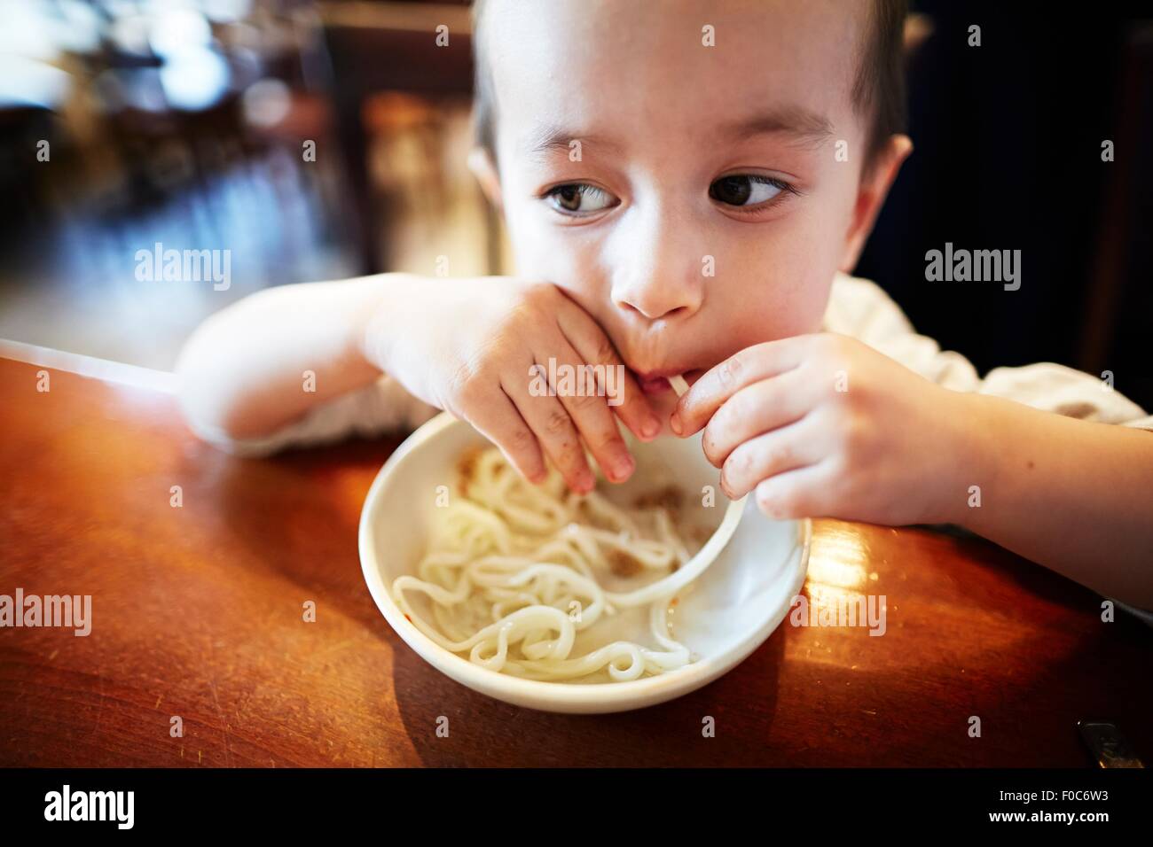 Boy eating noodles in restaurant Stock Photo - Alamy