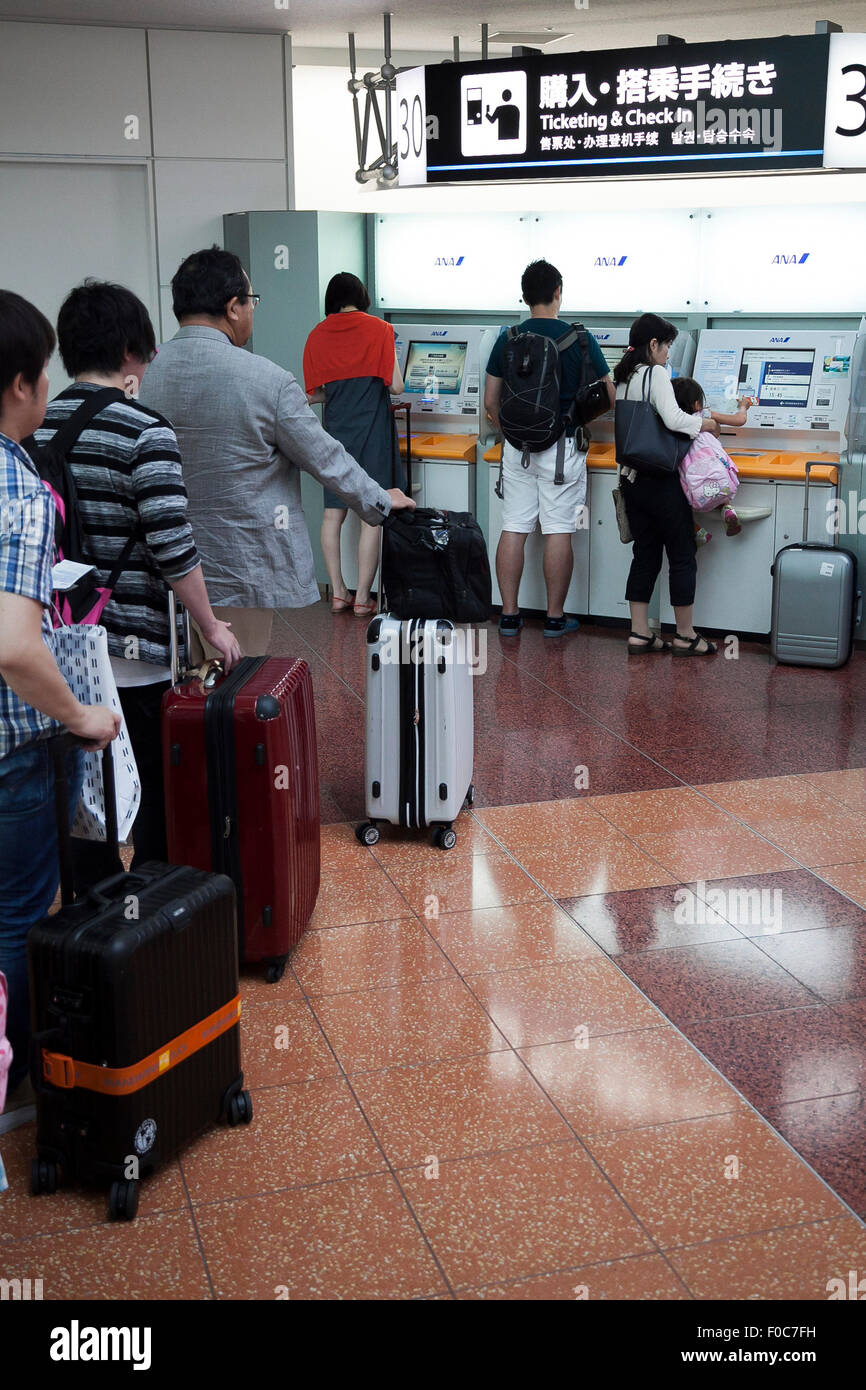 Passengers queue at a check-in desk at Haneda Airport Terminal 2 during ...