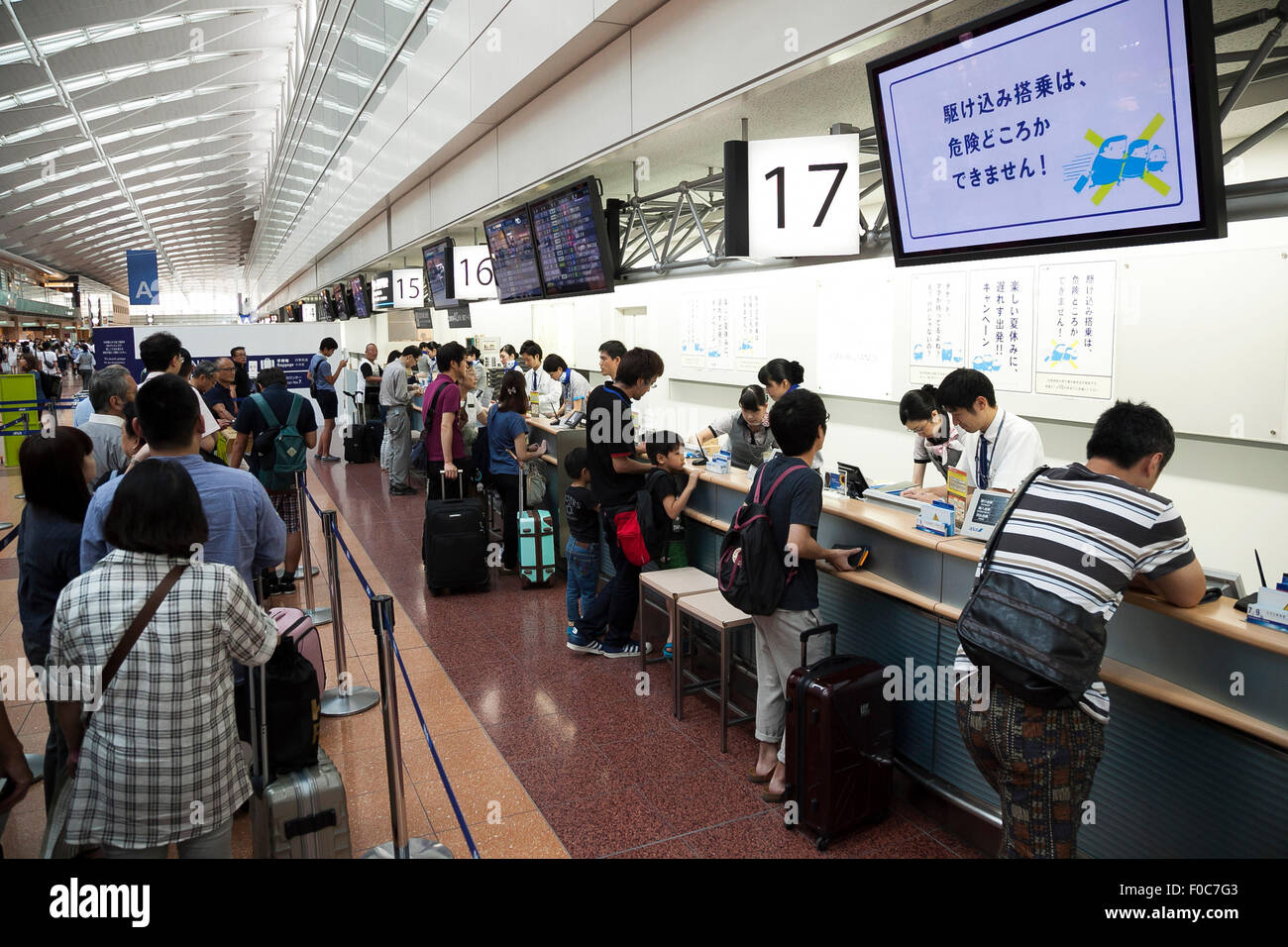 Passengers queue at a check-in desk at Haneda Airport Terminal 2 during ...