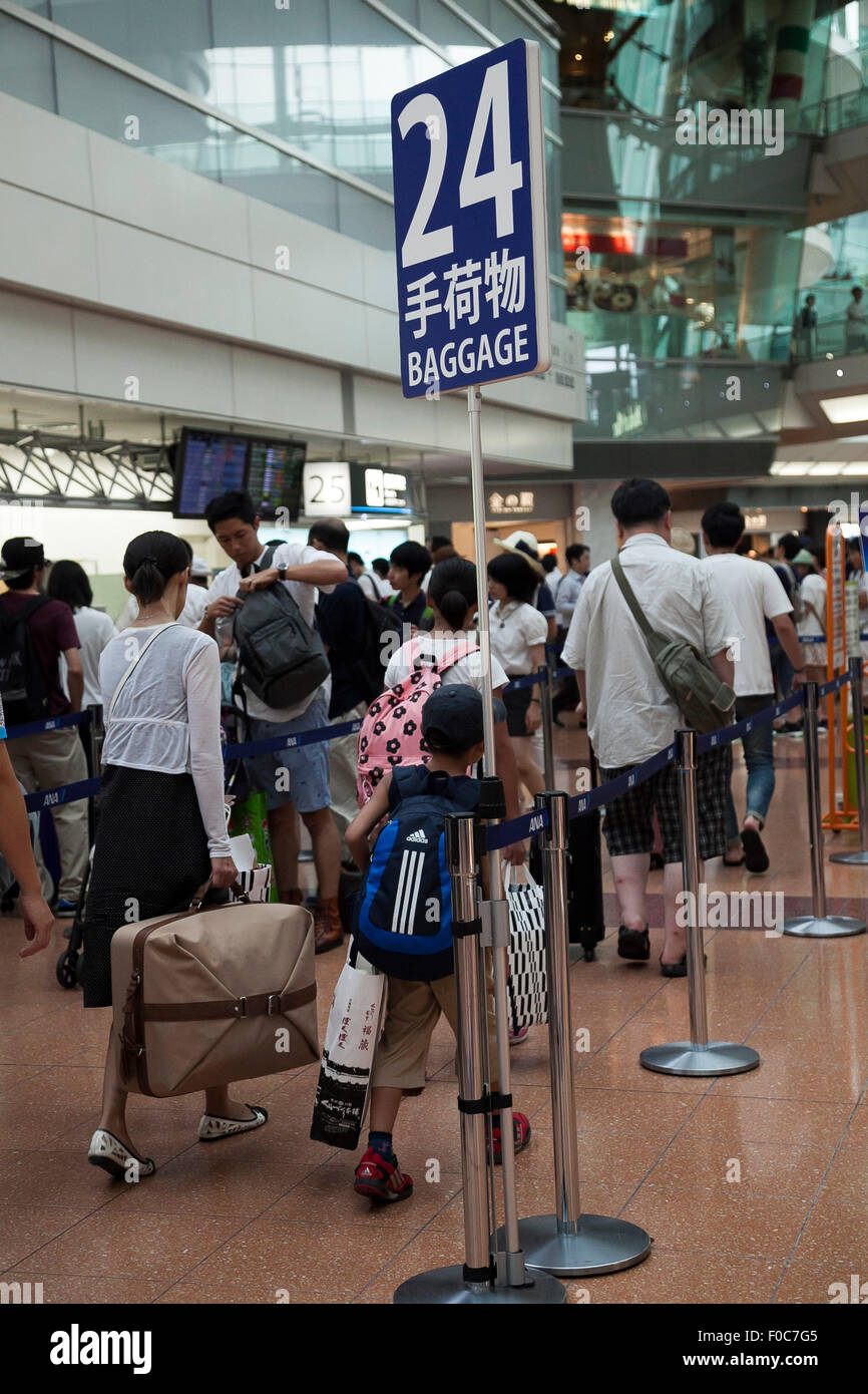 Passengers queue at a check-in desk at Haneda Airport Terminal 2 during ...