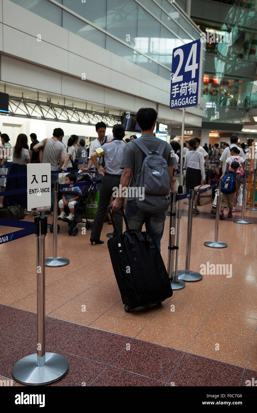 Passengers queue at a check-in desk at Haneda Airport Terminal 2 during ...