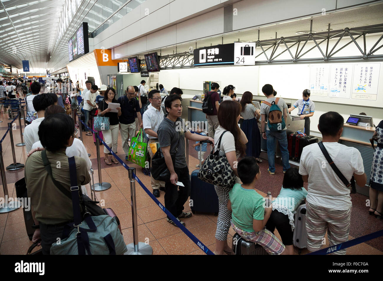 Passengers queue at a check-in desk at Haneda Airport Terminal 2 during ...