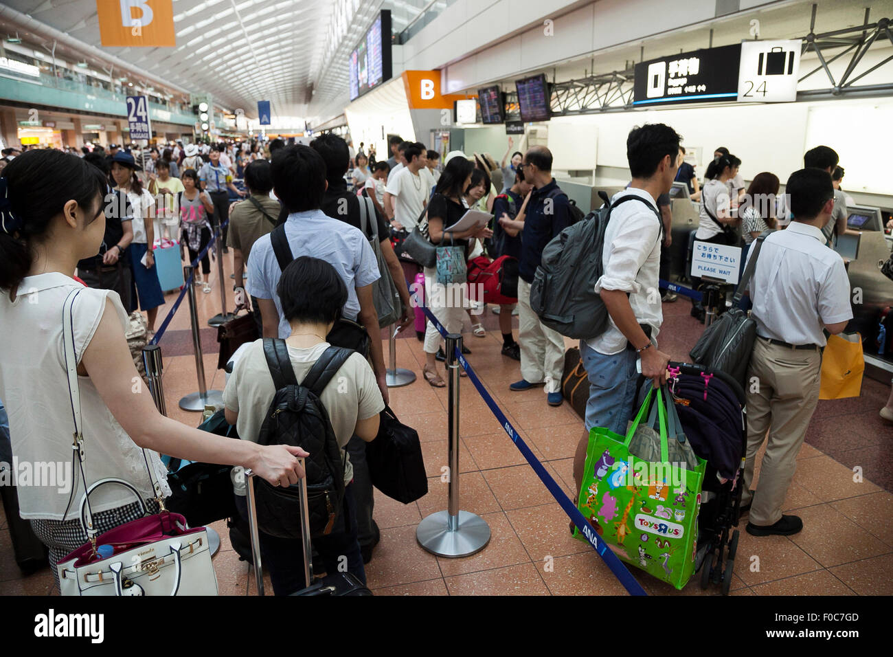 Passengers queue at a check-in desk at Haneda Airport Terminal 2 during ...