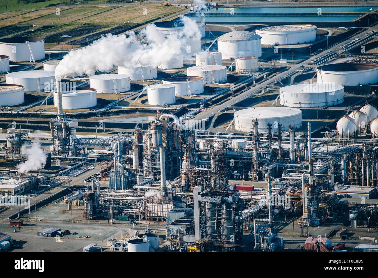 Rows of white oil storage tanks and smoke stack in oil refinery Stock ...