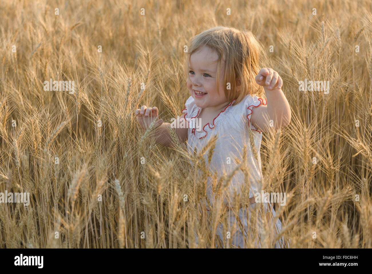 Happy girl walking in wheat field Stock Photo - Alamy