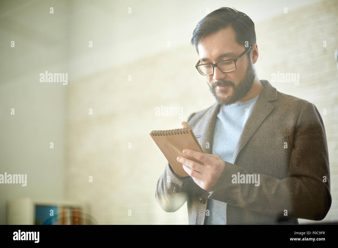 Young Asian businessman making notes in notepad Stock Photo - Alamy