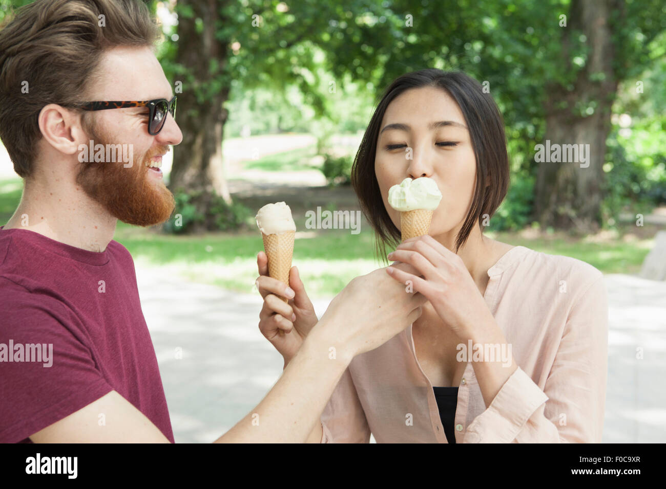Happy man feeding ice cream to woman at park Stock Photo - Alamy