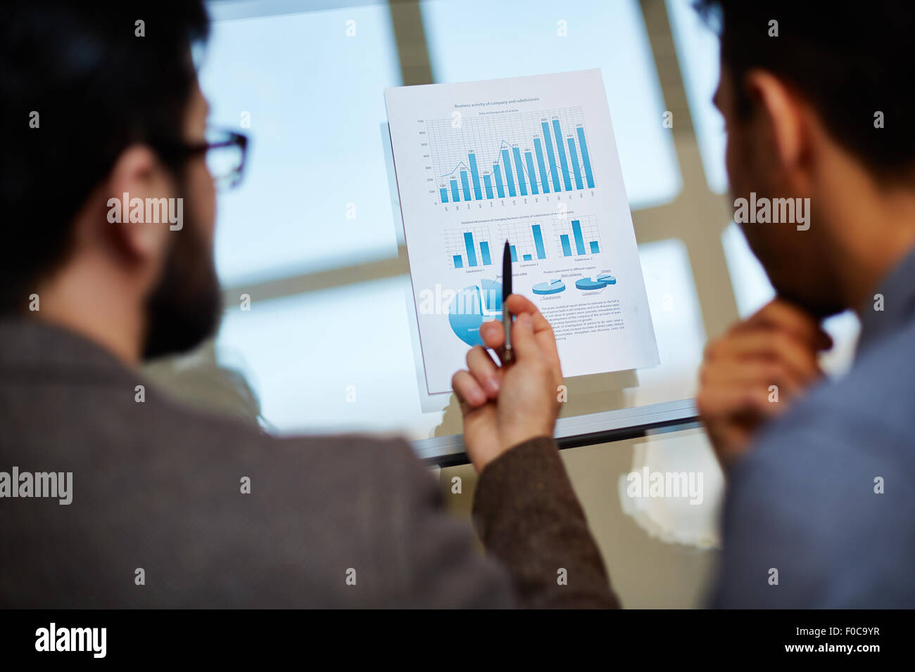Businessman explaining chart in document to colleague Stock Photo - Alamy