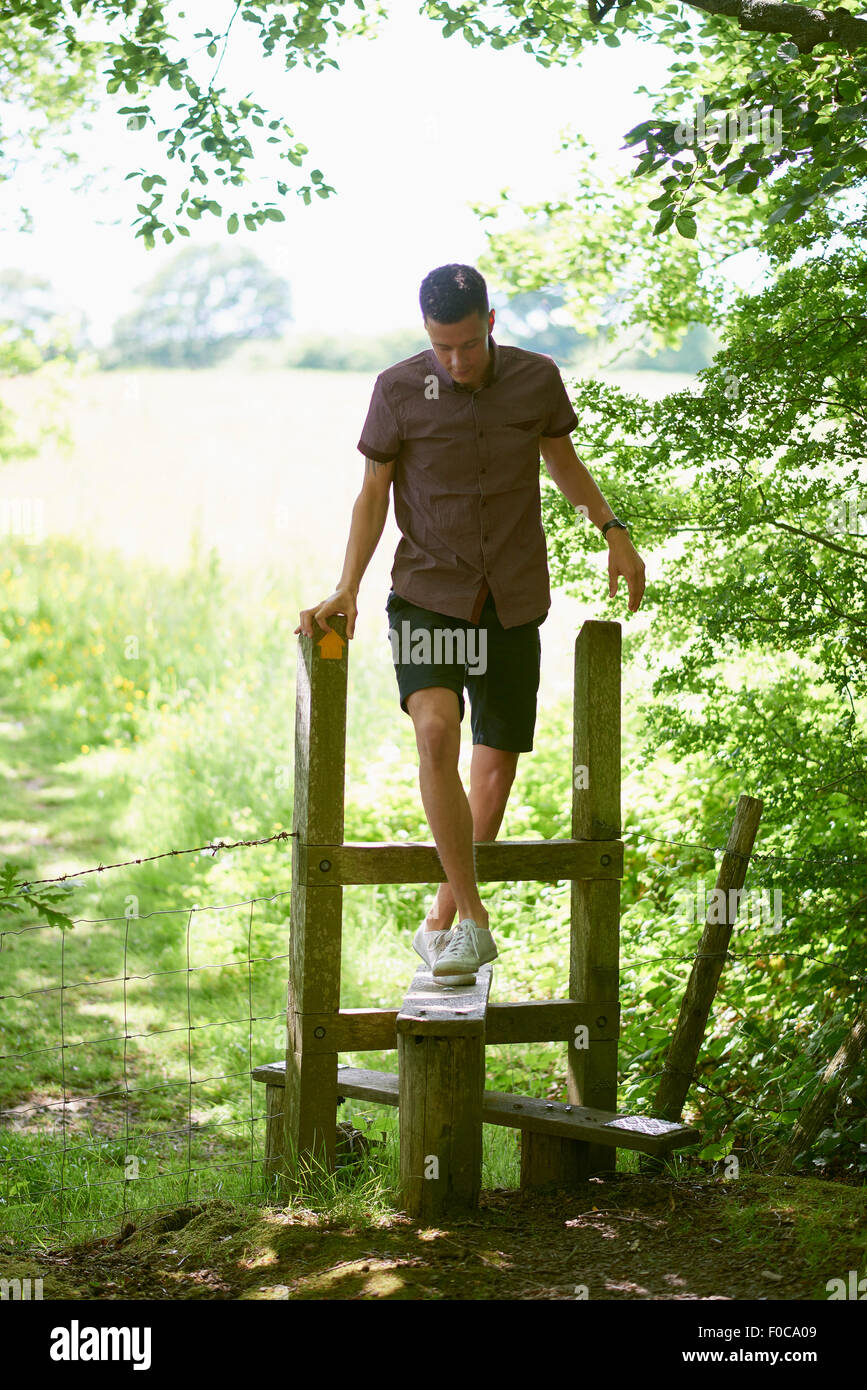 Full length of young man climbing fence in park Stock Photo - Alamy