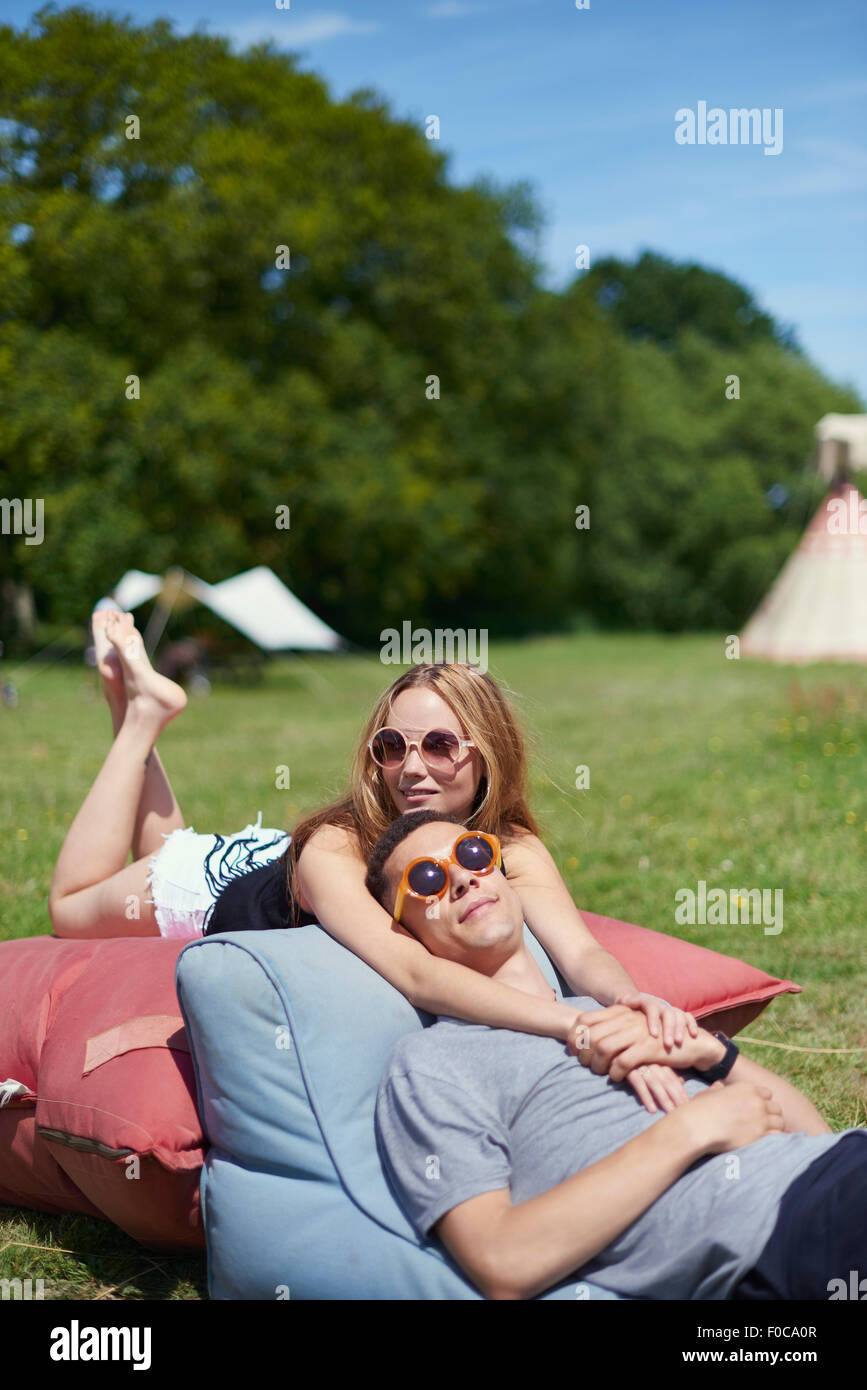 Loving couple lying on pillows while glamping, teepee in background ...