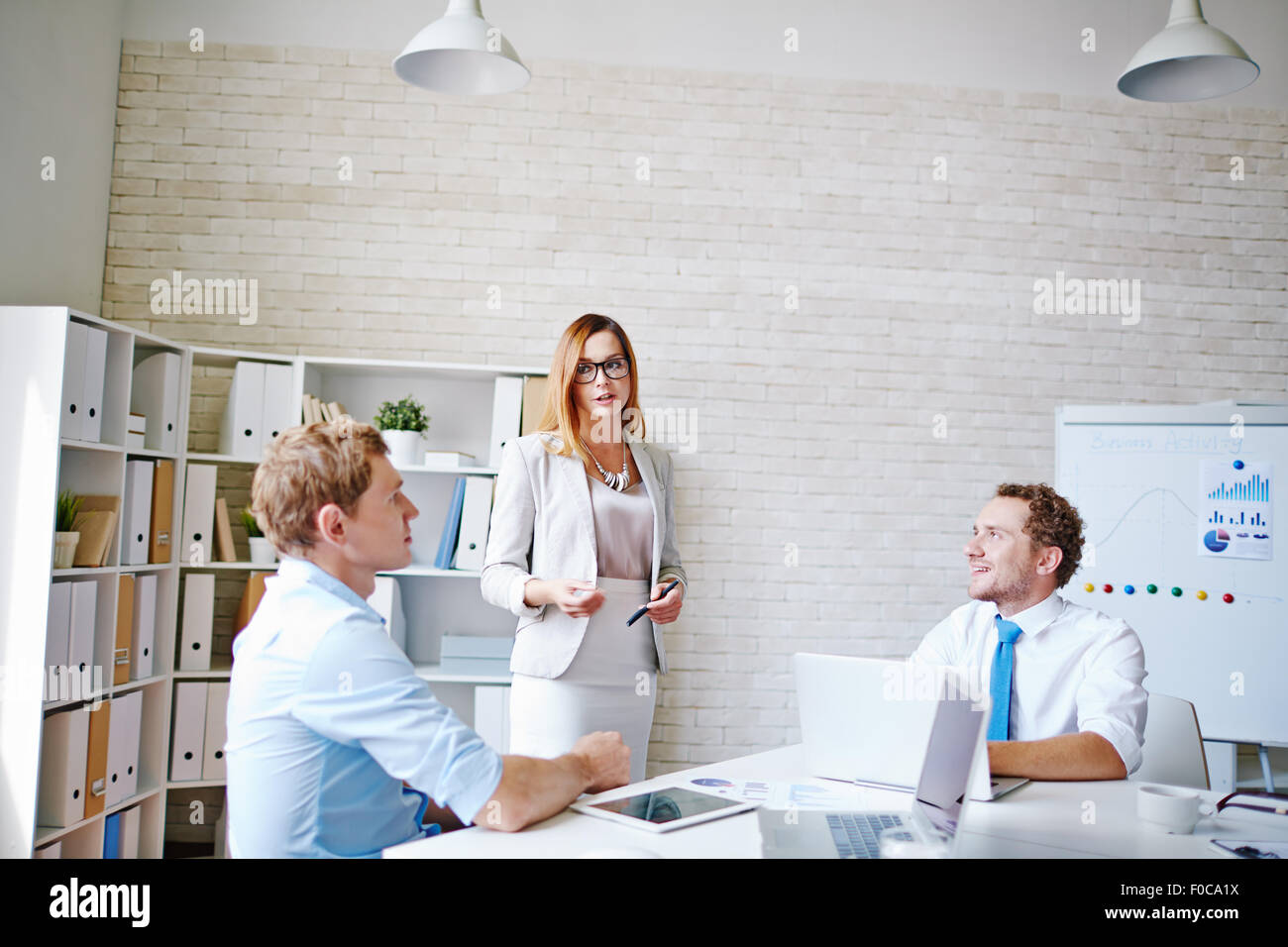 Elegant employee explaining financial data to colleagues Stock Photo ...