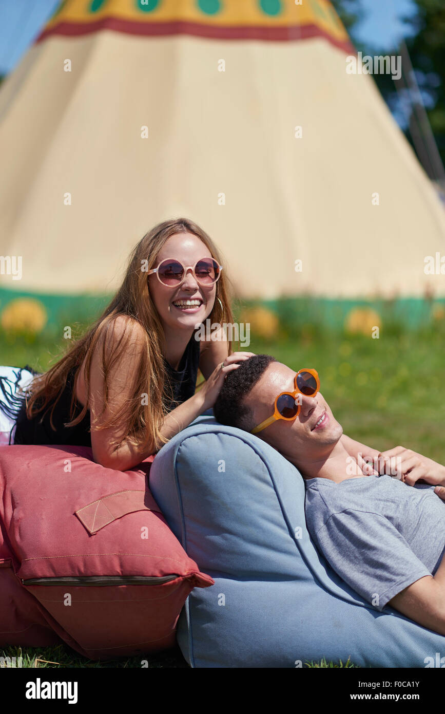 Happy couple lying on pillows while glamping, teepee in background ...